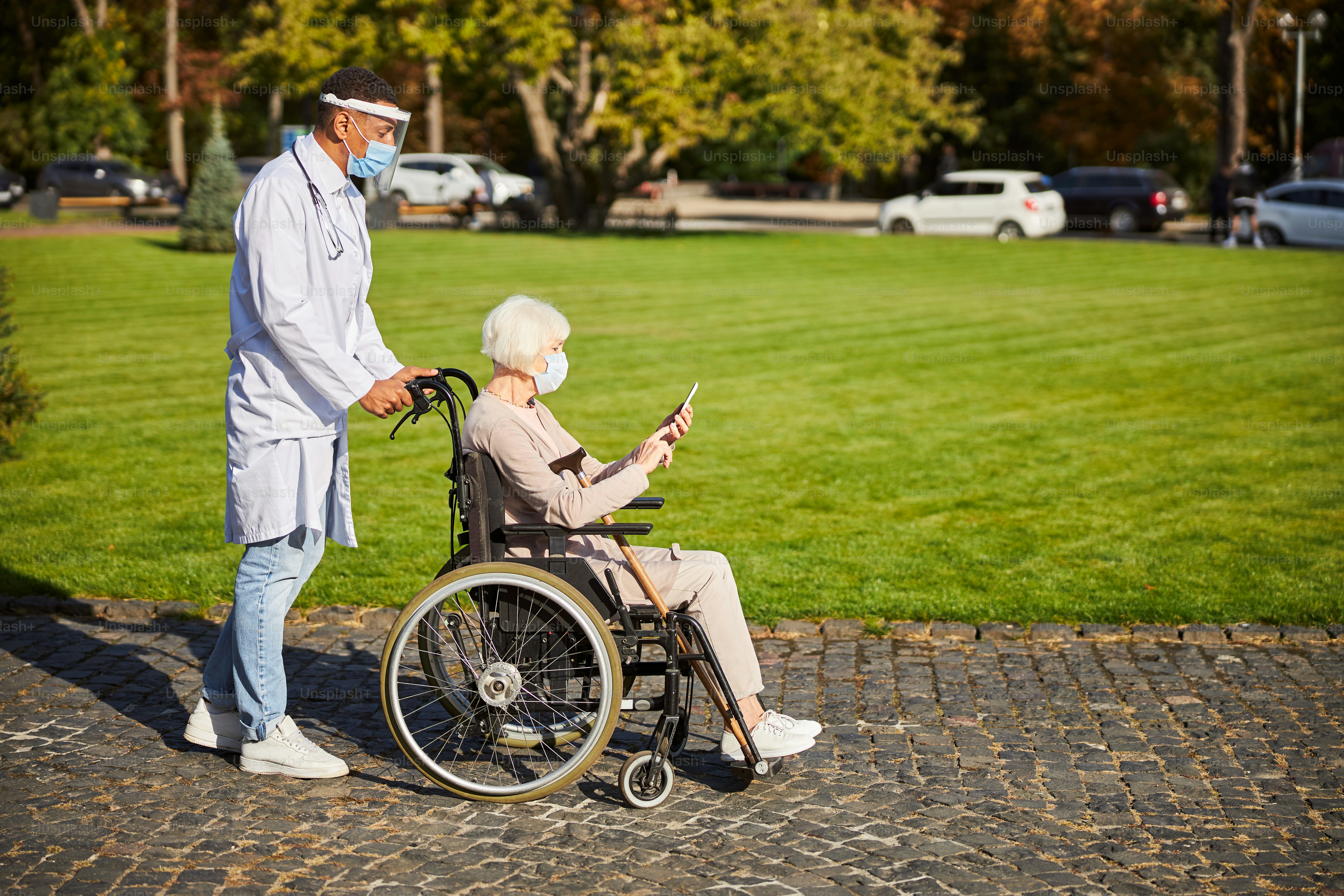 Elderly lady sitting with a smartphone in hands while a medical worker ...