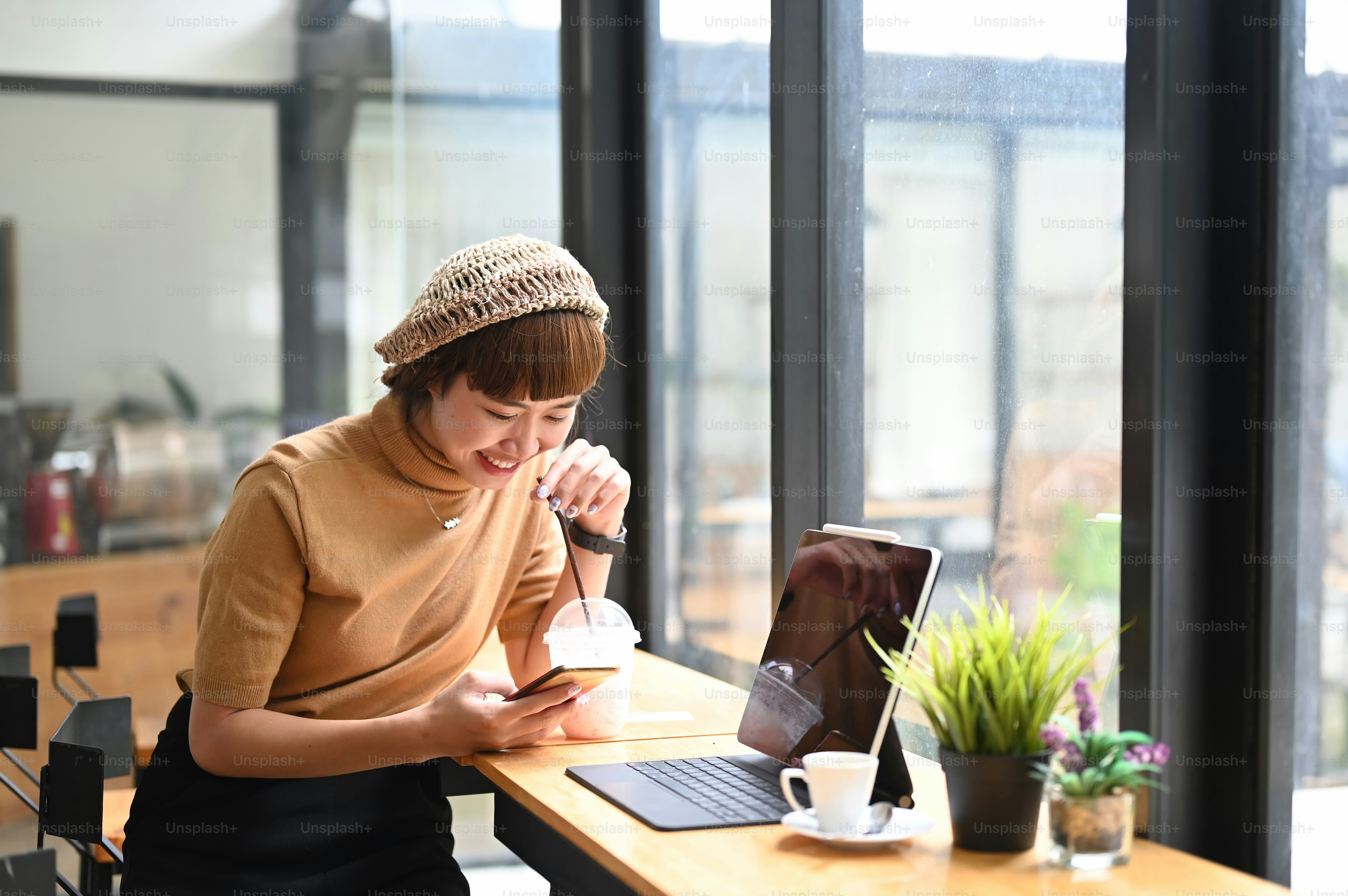 Shot of young female using smartphone atn her workstation. photo ...