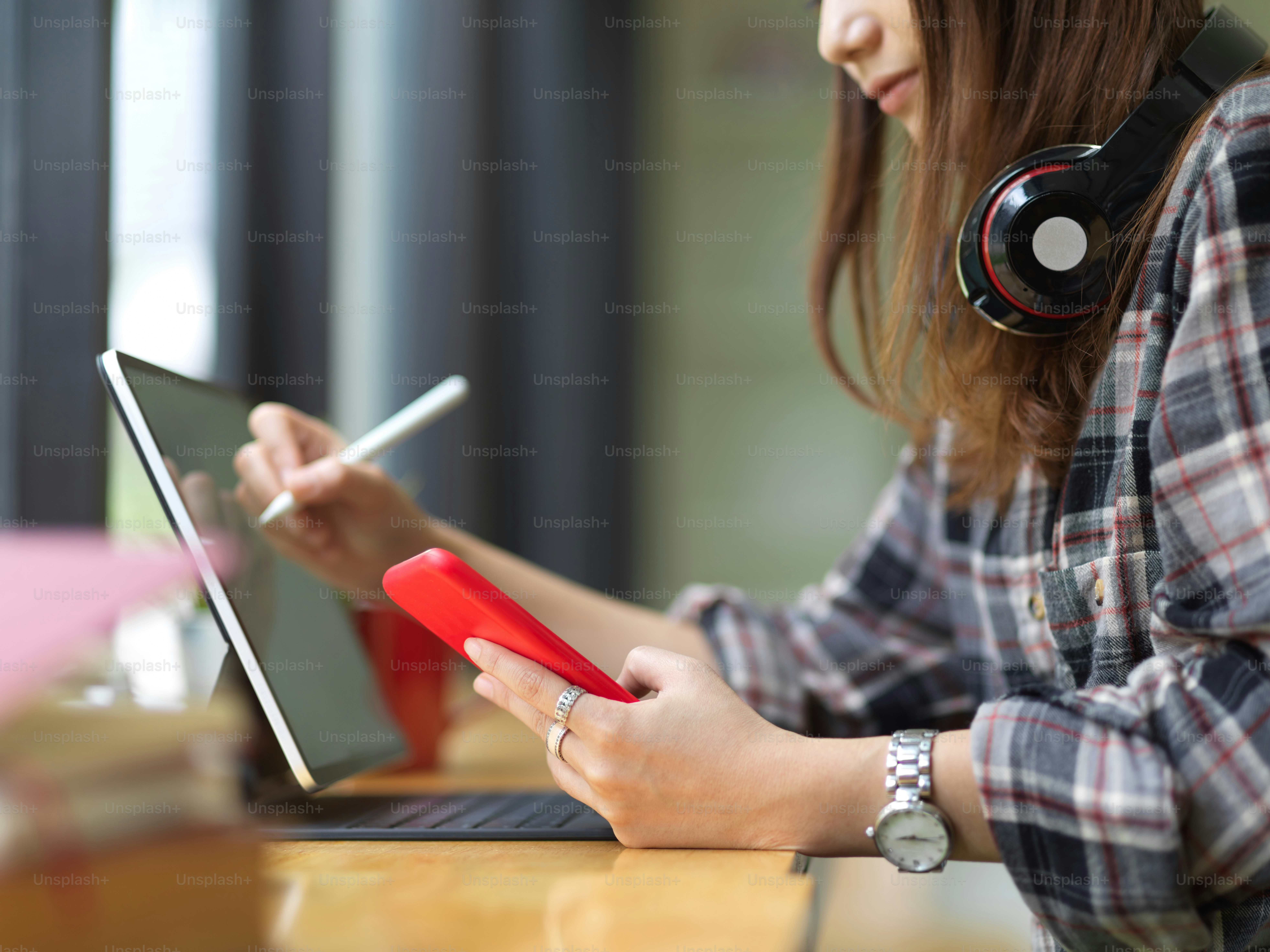 Side view of female teenager with headphone using digital tablets and smartphone in cafe photo ...