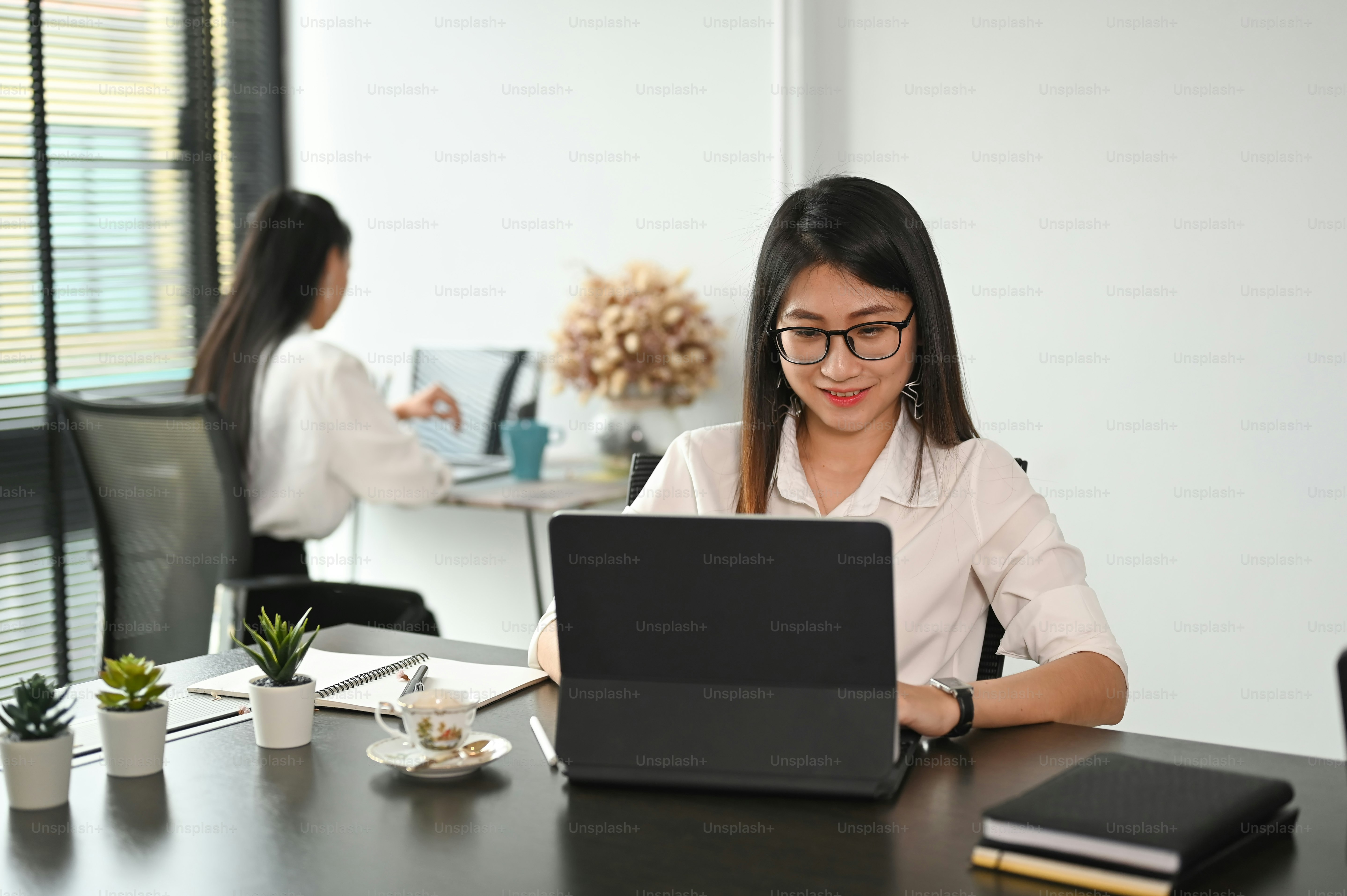 Happy young woman using tablet computer for work in office. photo ...