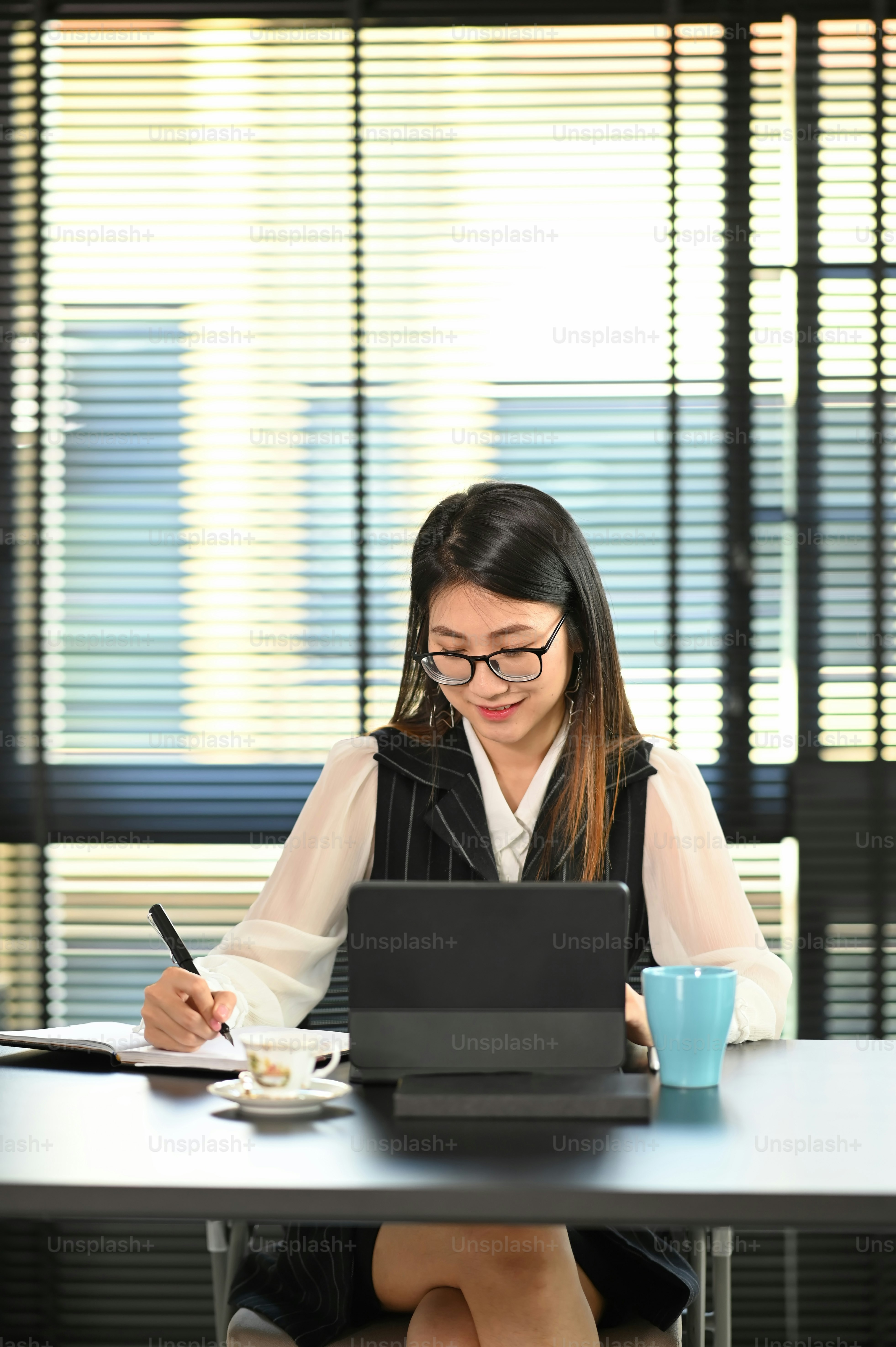 Creative female office worker using computer tablet and writing on ...