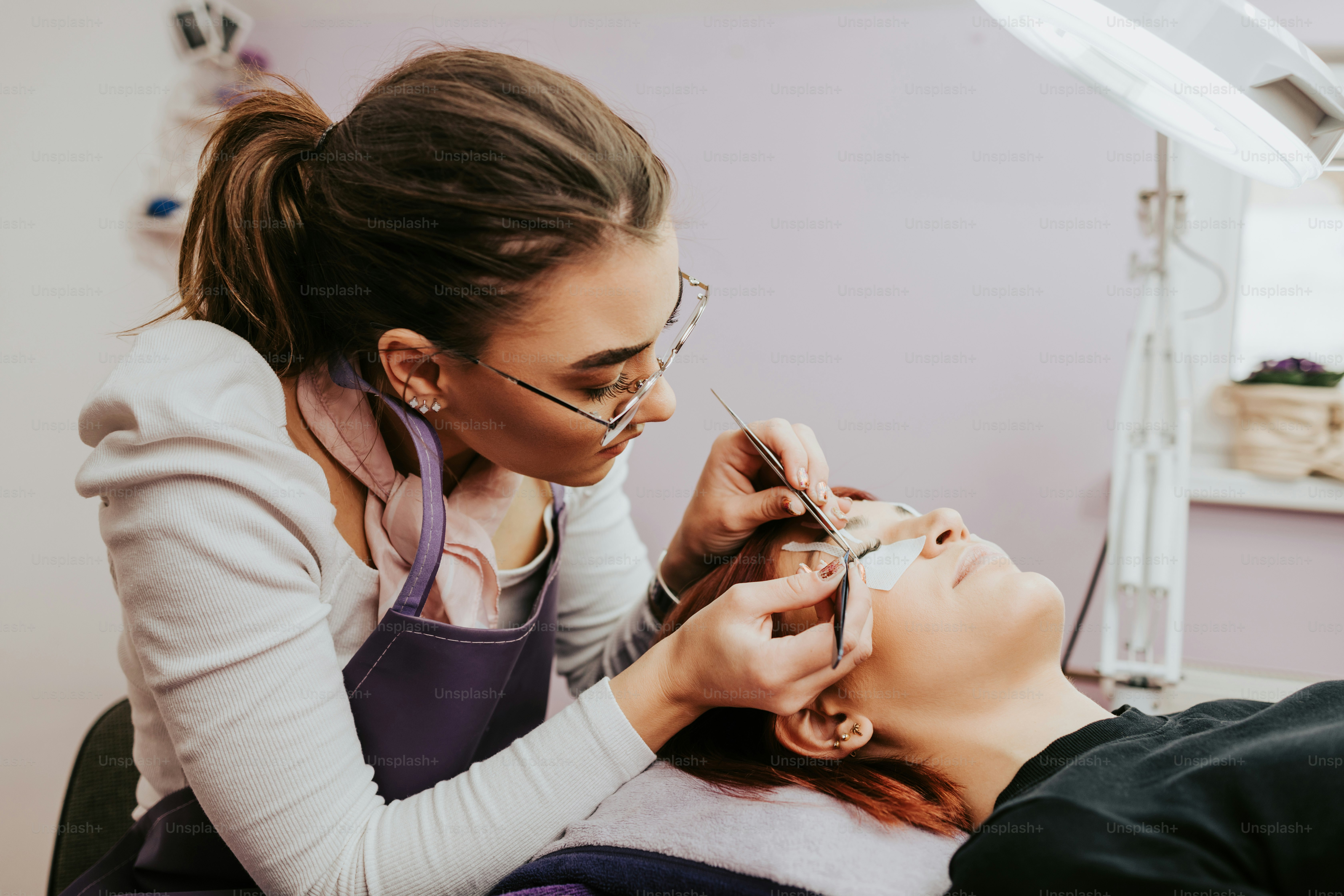 Beautiful young woman at eyelash extension procedure. Cosmetics and ...