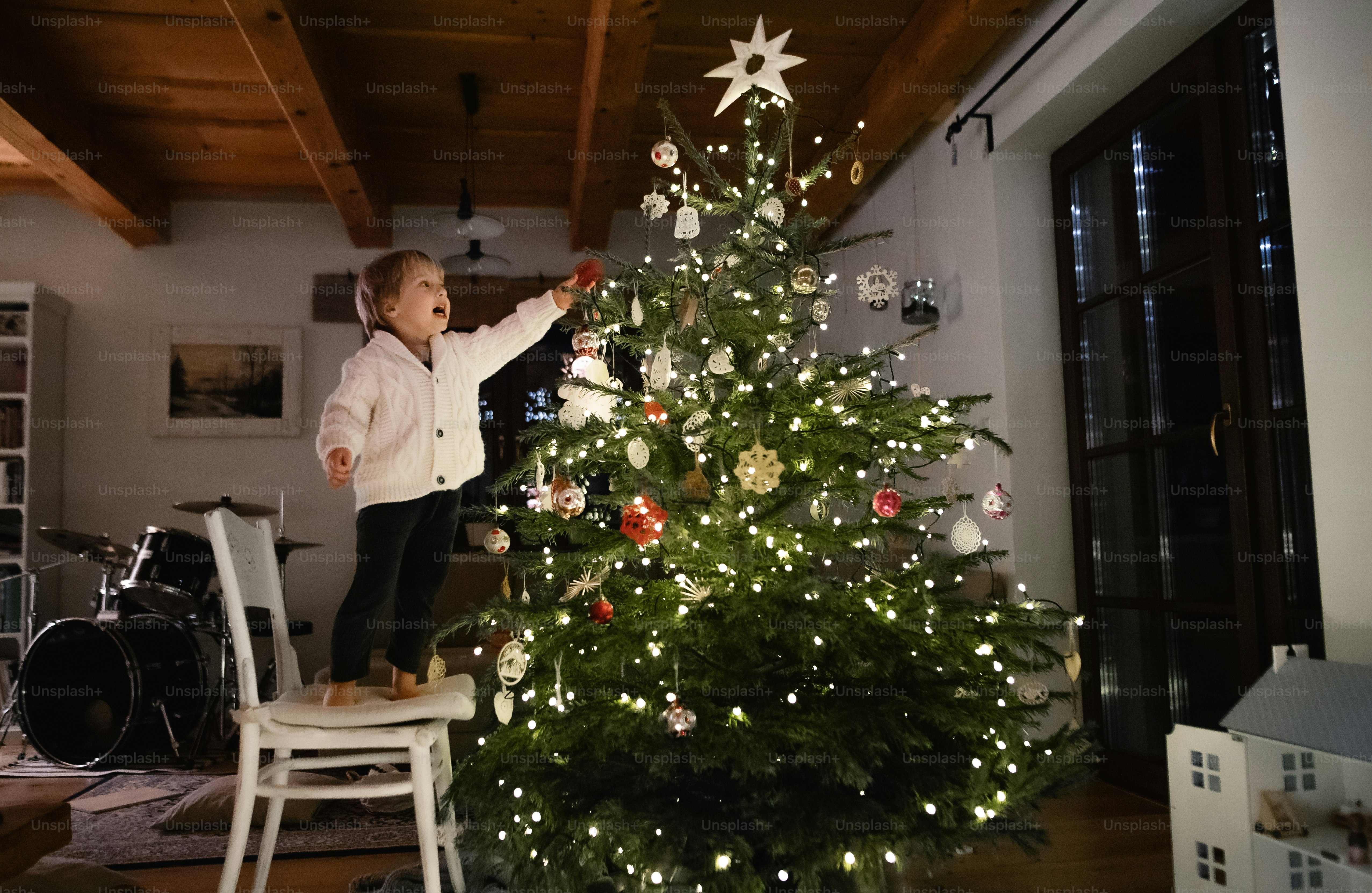 Portrait of happy small boy indoors at home at Christmas, decorating ...