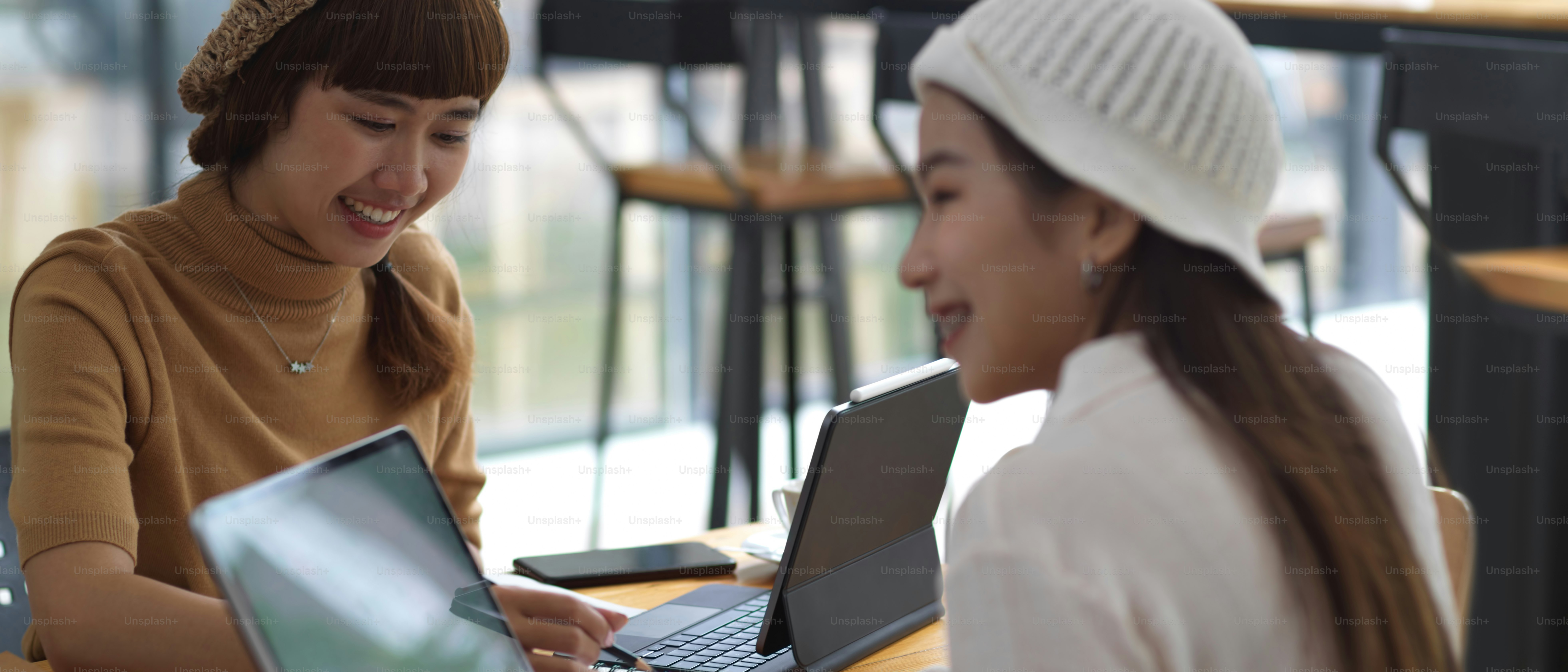 Portrait of two female students doing group assignment together with ...