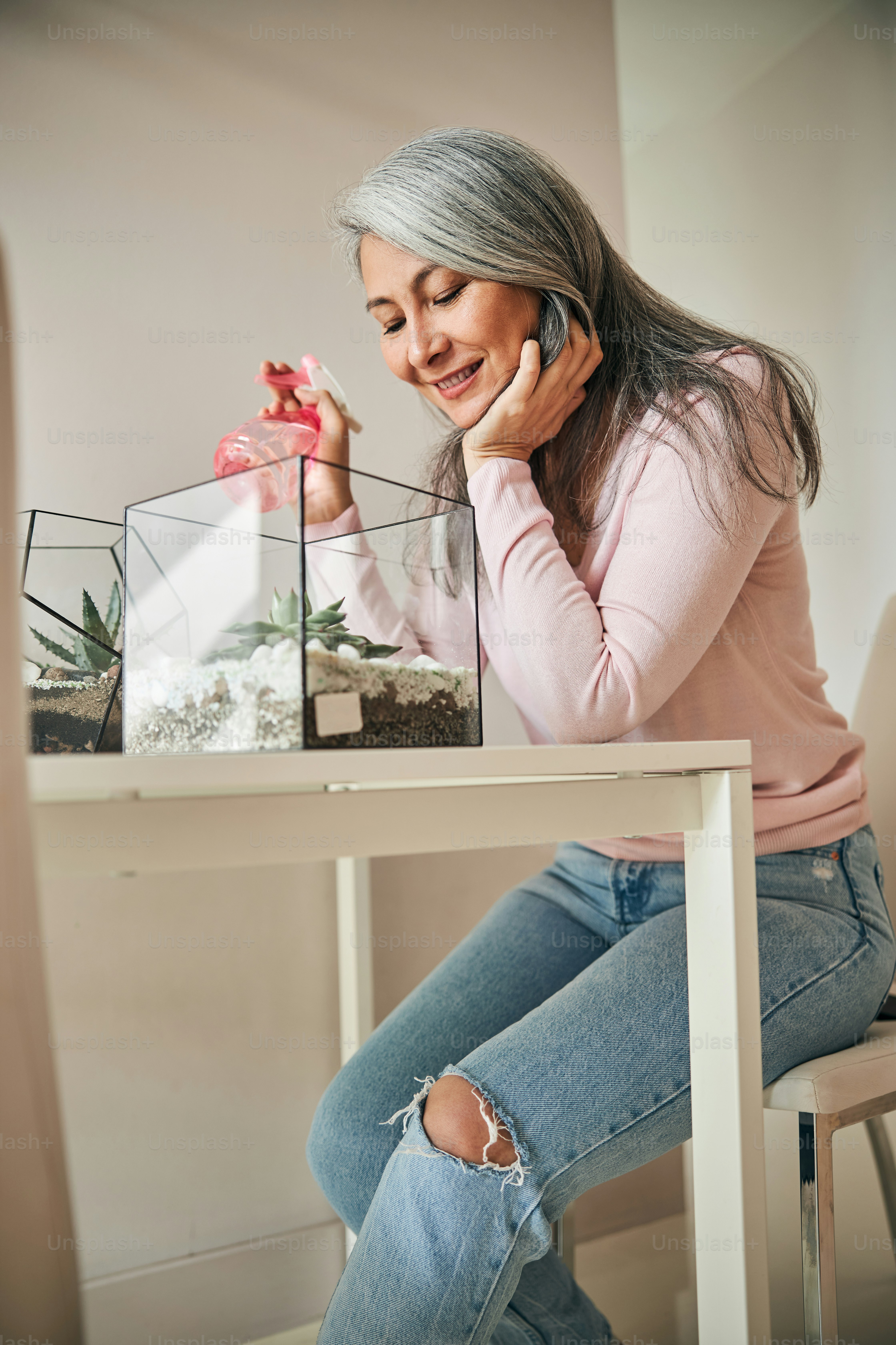 Beautiful lady holding water spray bottle and smiling while sitting at ...