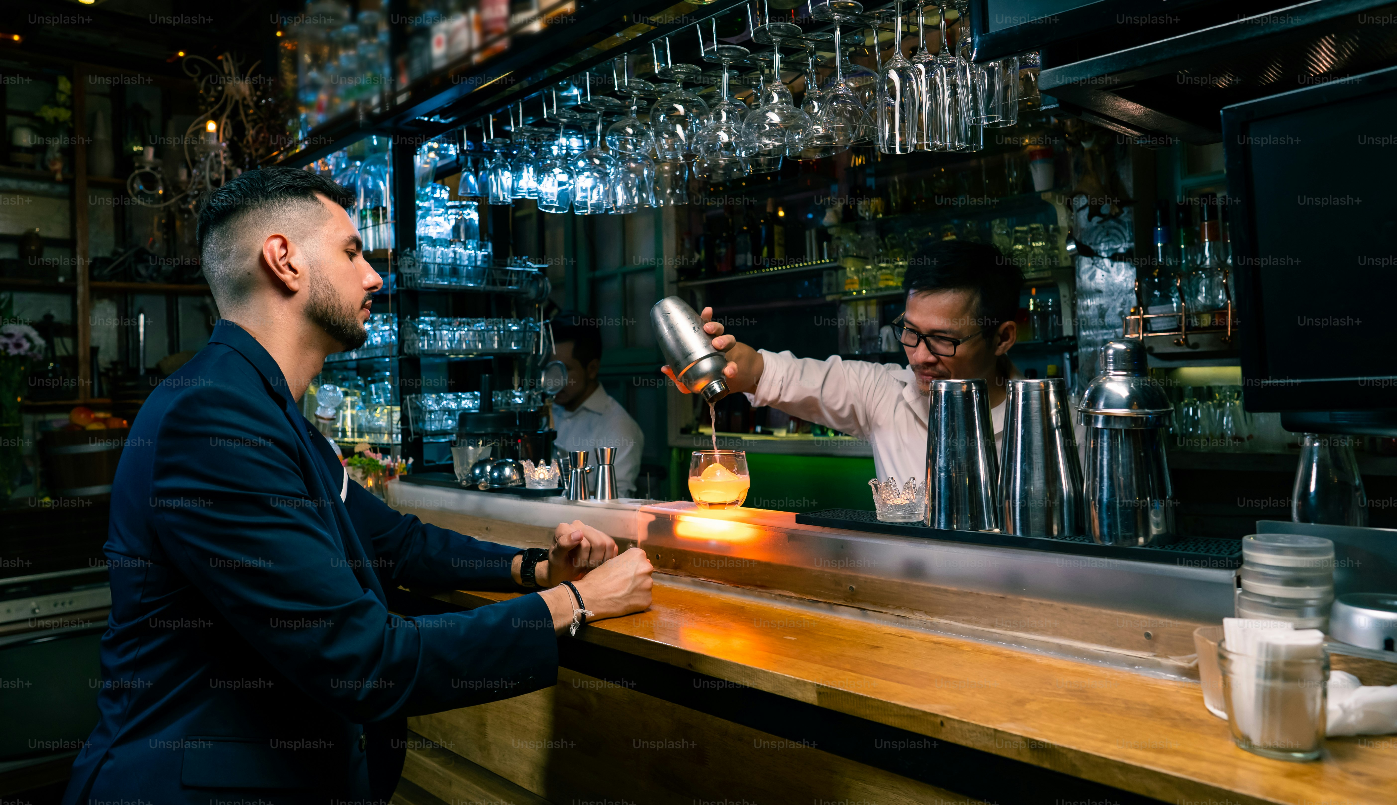 Caucasian man sitting at bar counter waiting cocktail drink from barman ...