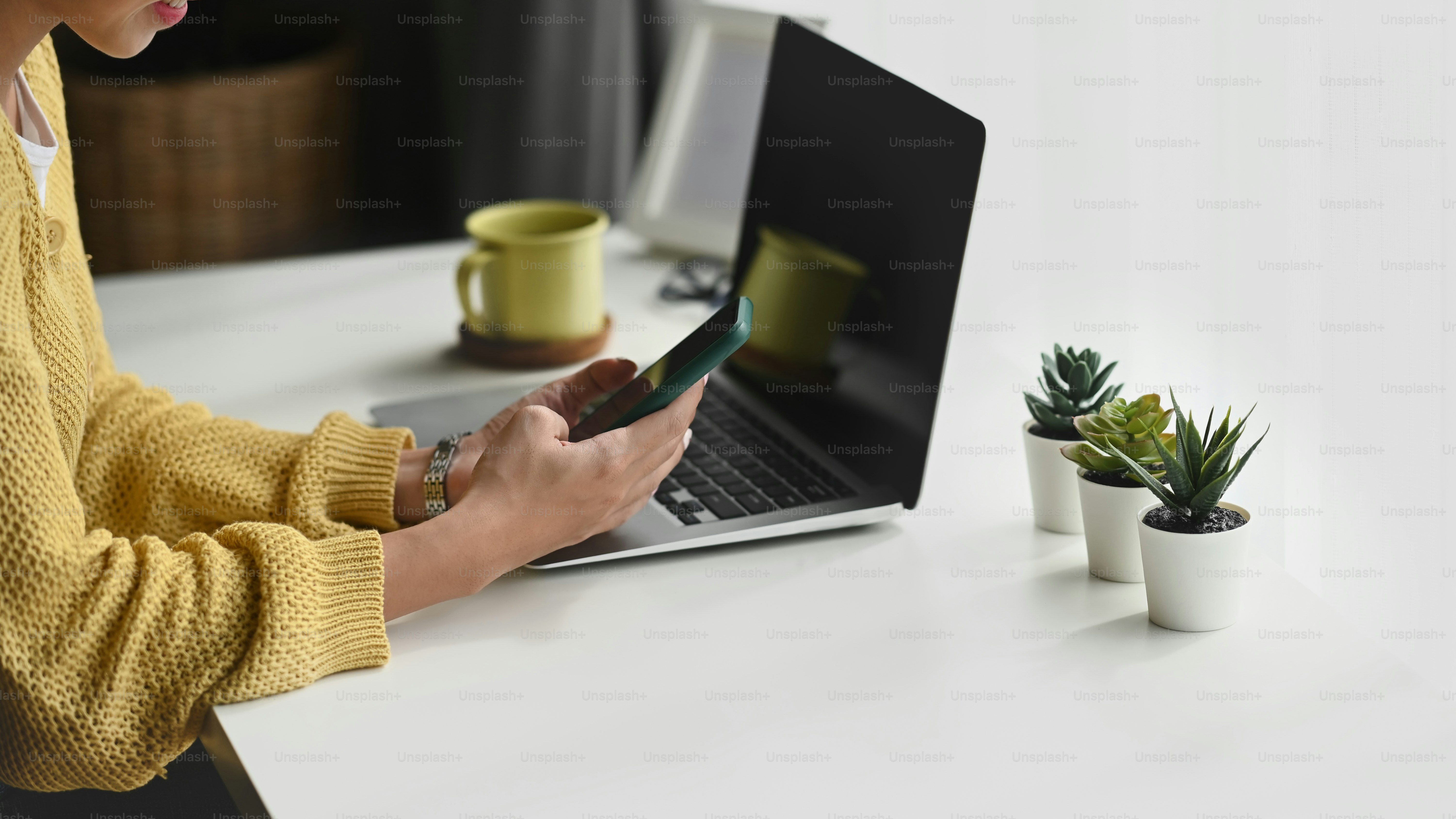 Cropped shot of young female freelancer using smartphone and laptop on ...