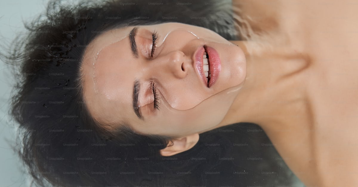 목욕하는 동안 물에 떠 있는 닫힌 눈을 가진 아름다운 고요한 아가씨 사진 Unsplash의 세로 이미지