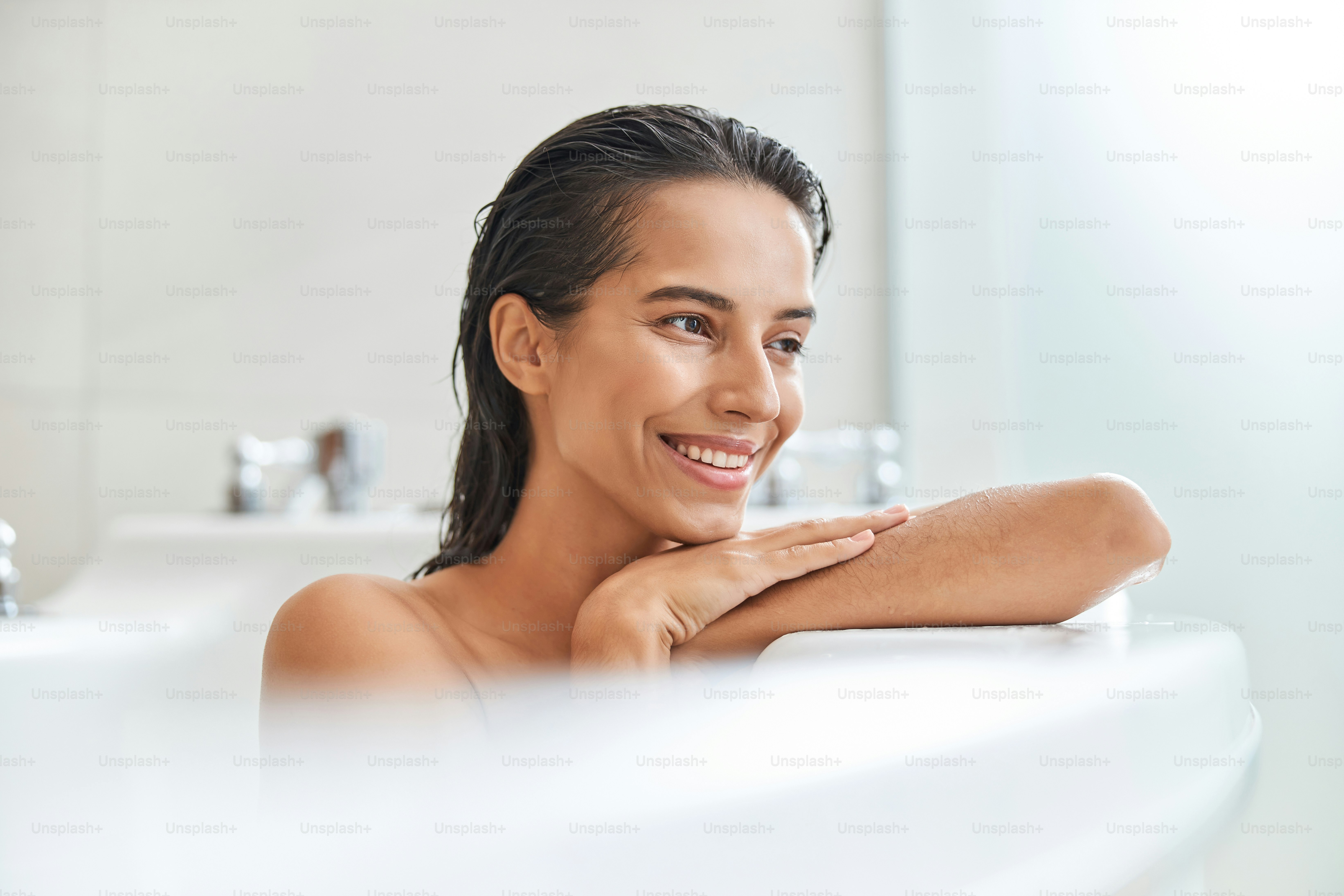 Attractive lady with wet hair looking away and smiling while relaxing ...