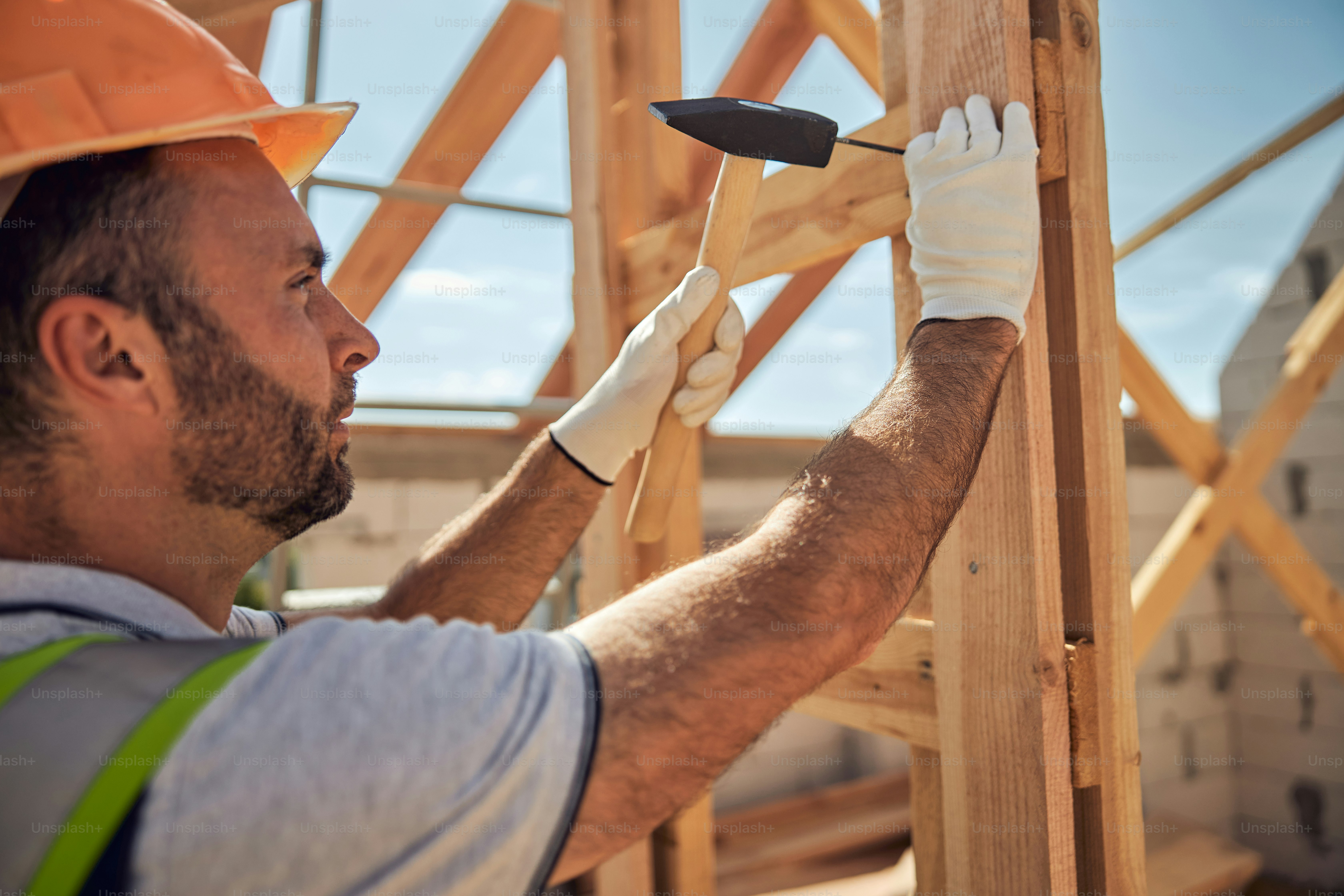Concentrated foreman standing in semi position while hammering nail ...