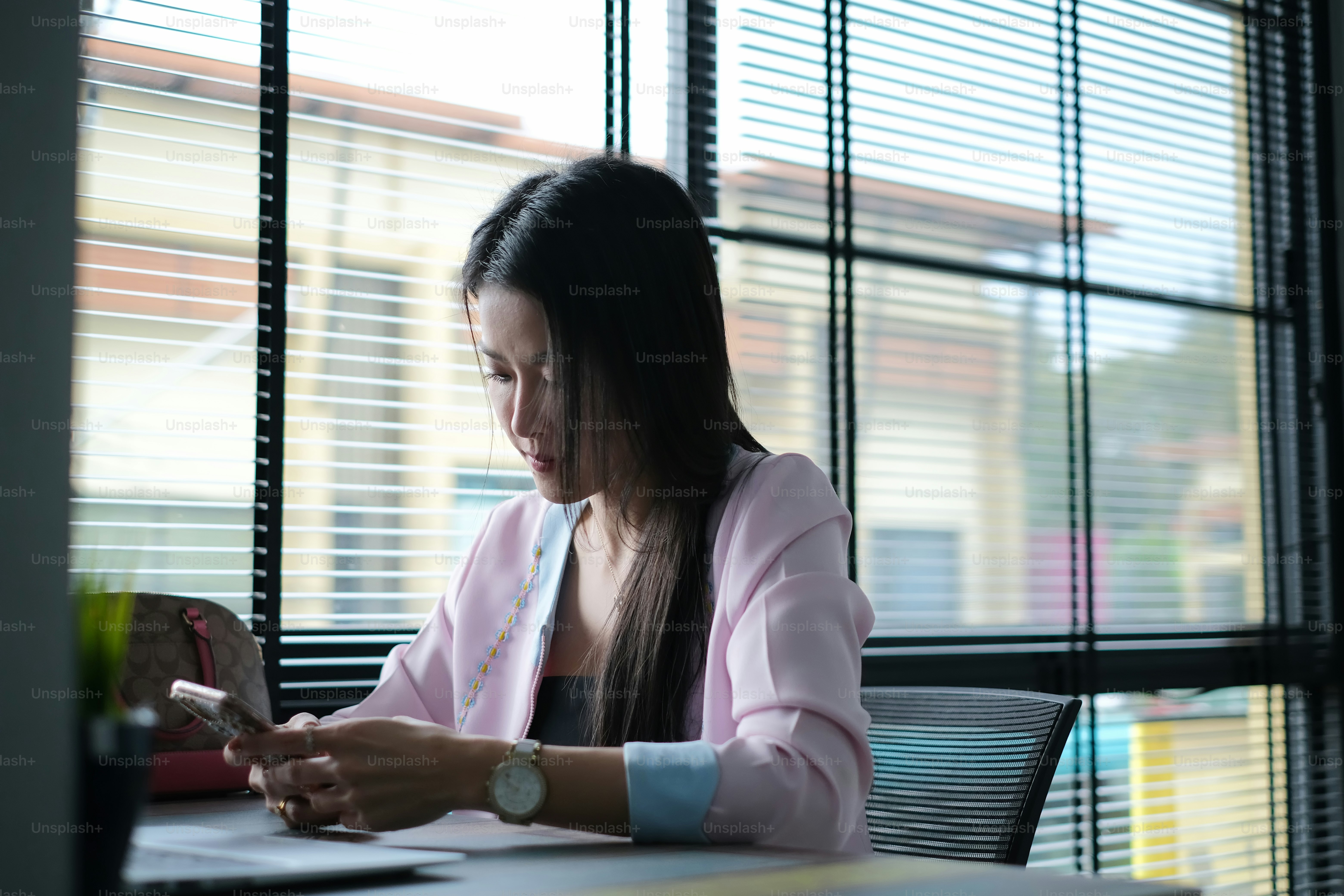 A young Asian businesswoman is working on laptop and using smart phone ...