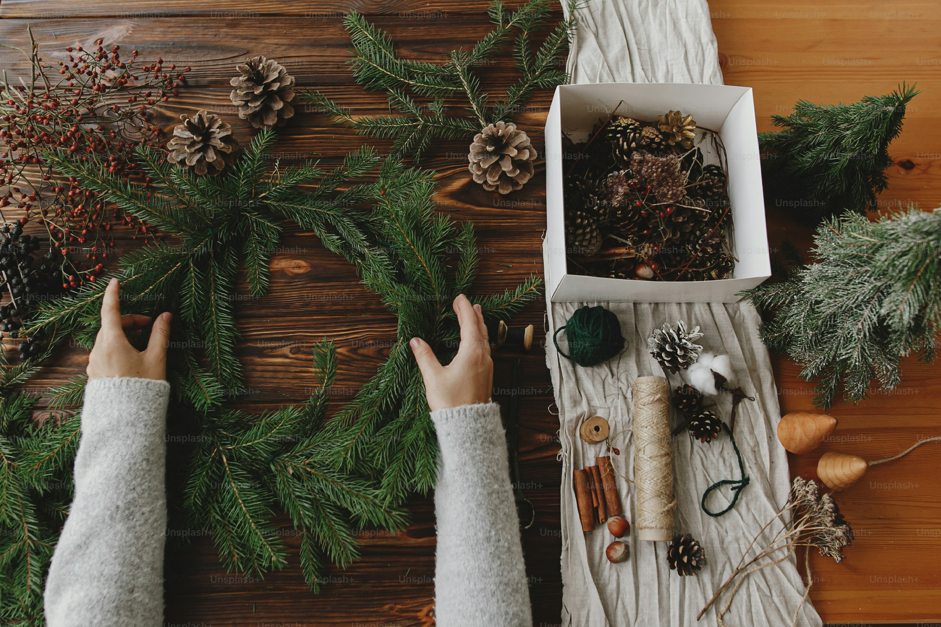 Foto Hacer una corona de navidad rústica plana. Manos sosteniendo ramas ...