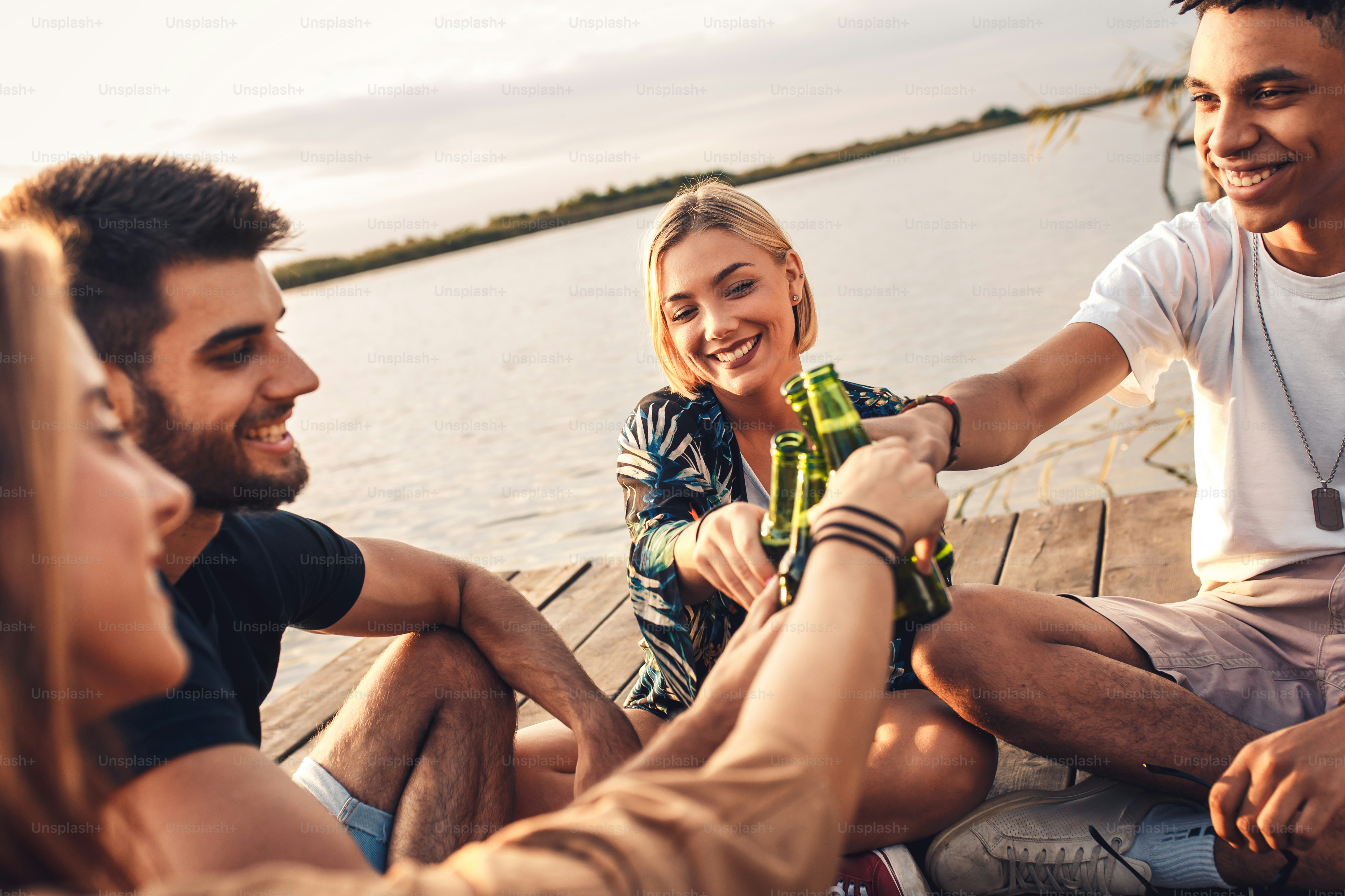 Group of friends enjoying a day at the lake. They sitting on pier ...