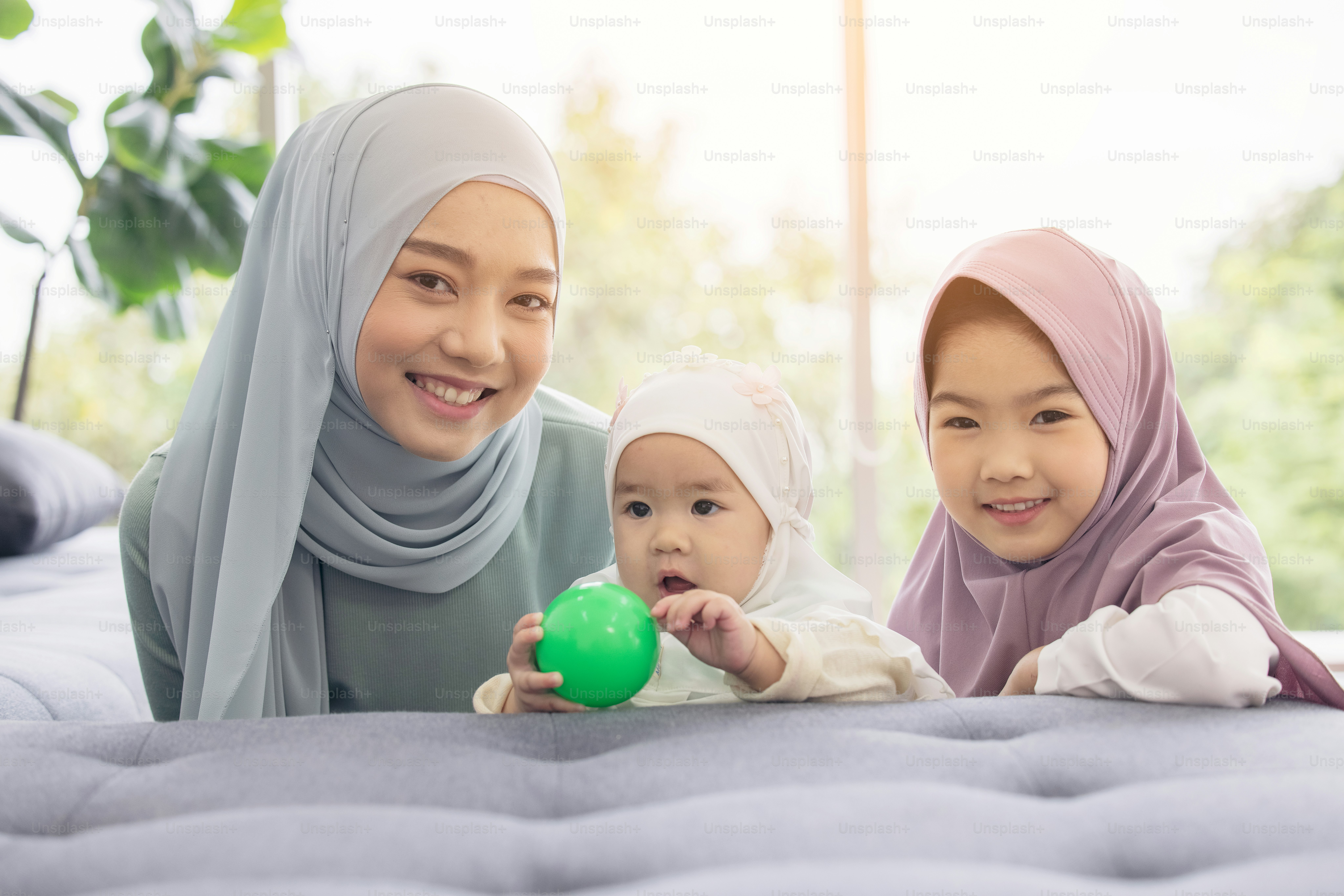 Muslim mom in hijab is her little daughter sitting in the living room ...