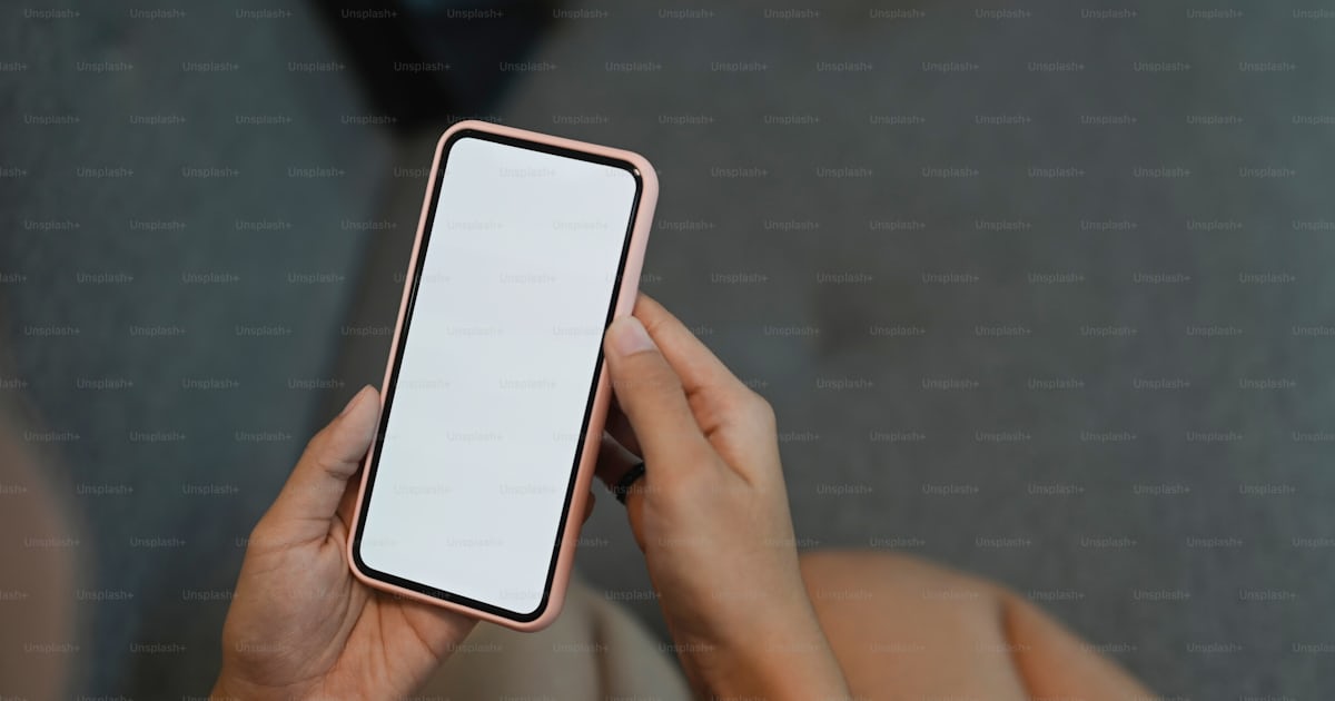 ソファに座っている間、空白の画面のスマートフォンを保持している女性の接写。グラフィック表示モンタージュの場合。の写真 Unsplashの空