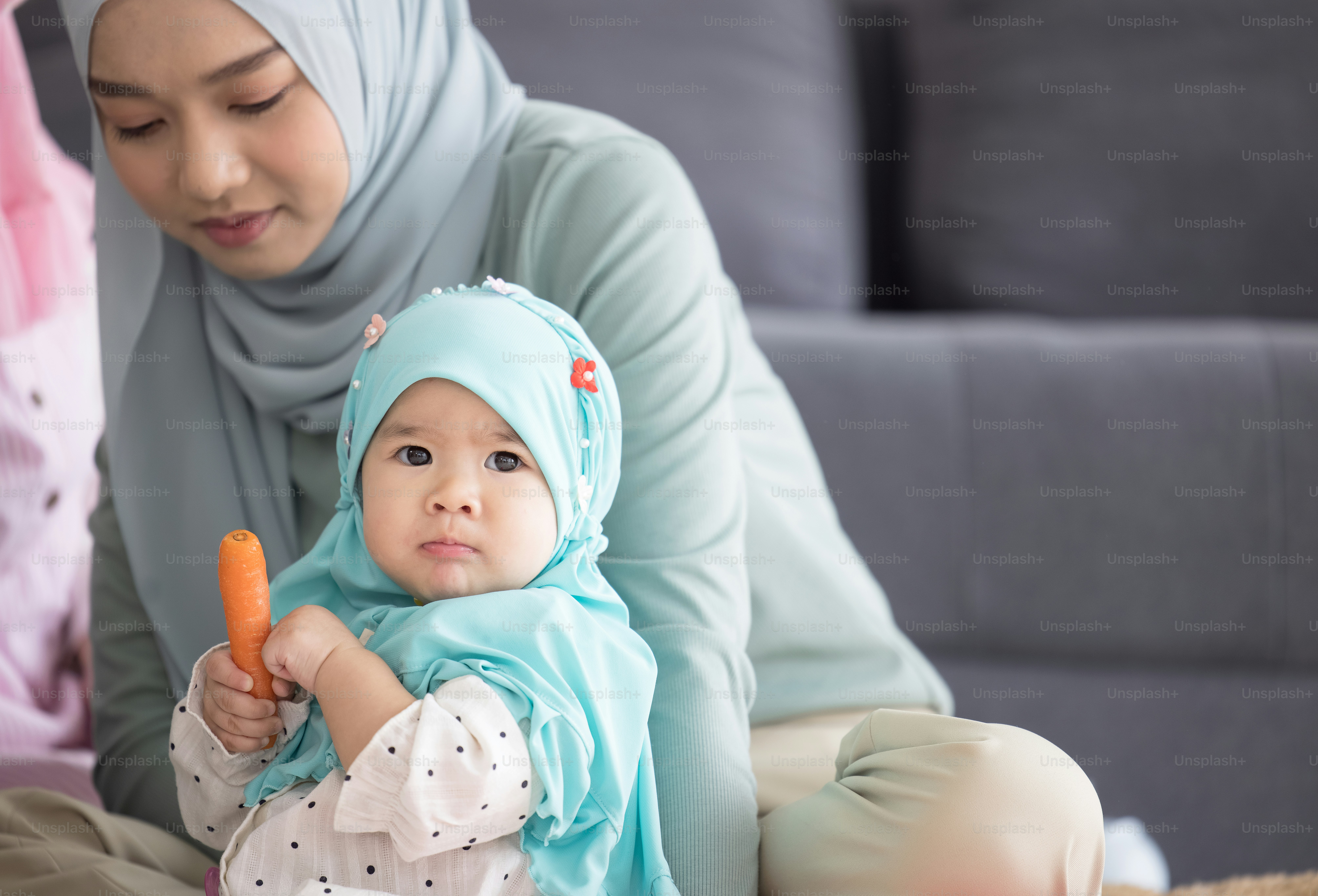 Muslim mom in hijab is her little daughter sitting in the living room ...