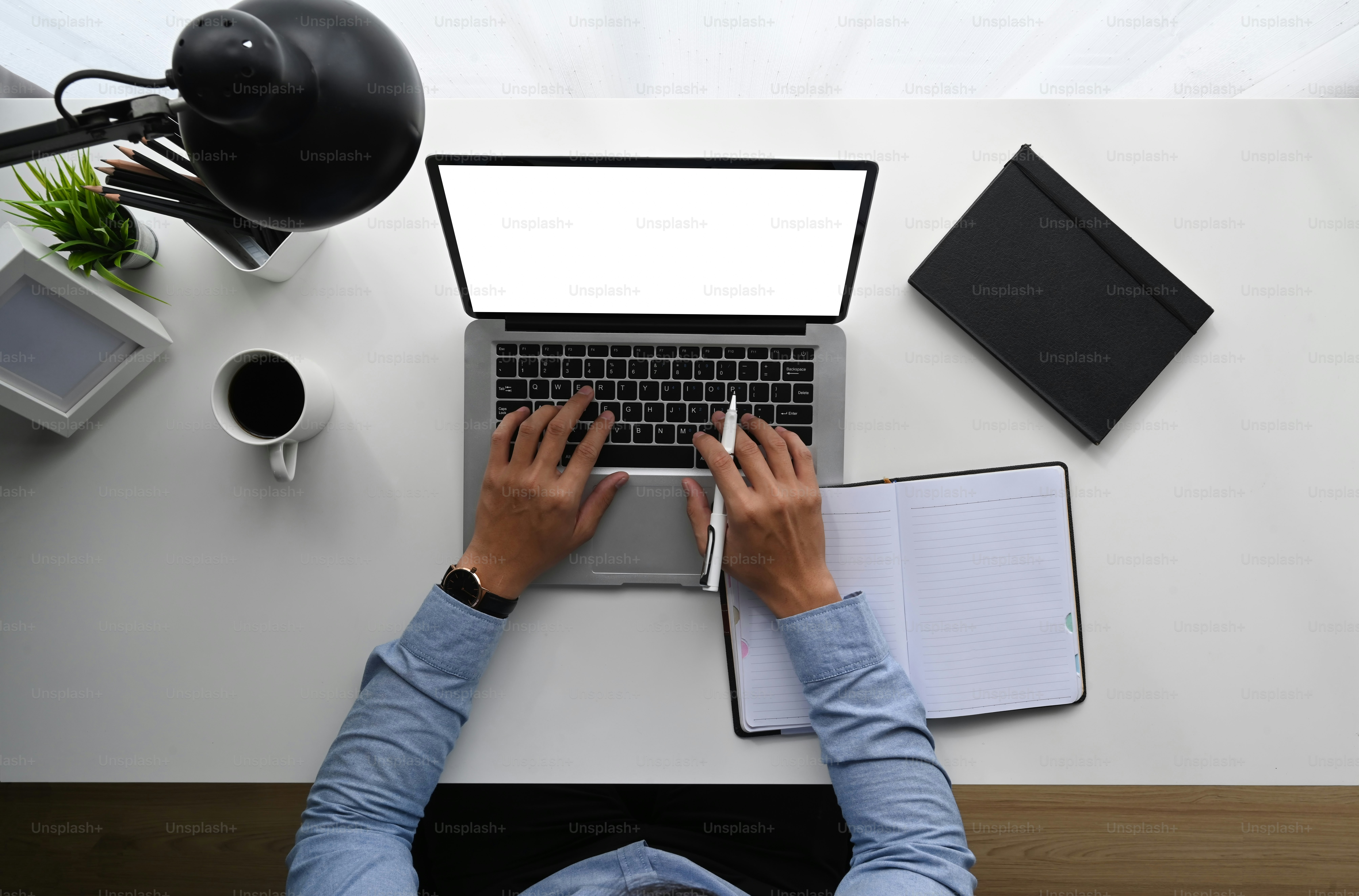 Top view of man is working on laptop while sitting at the white wooden ...