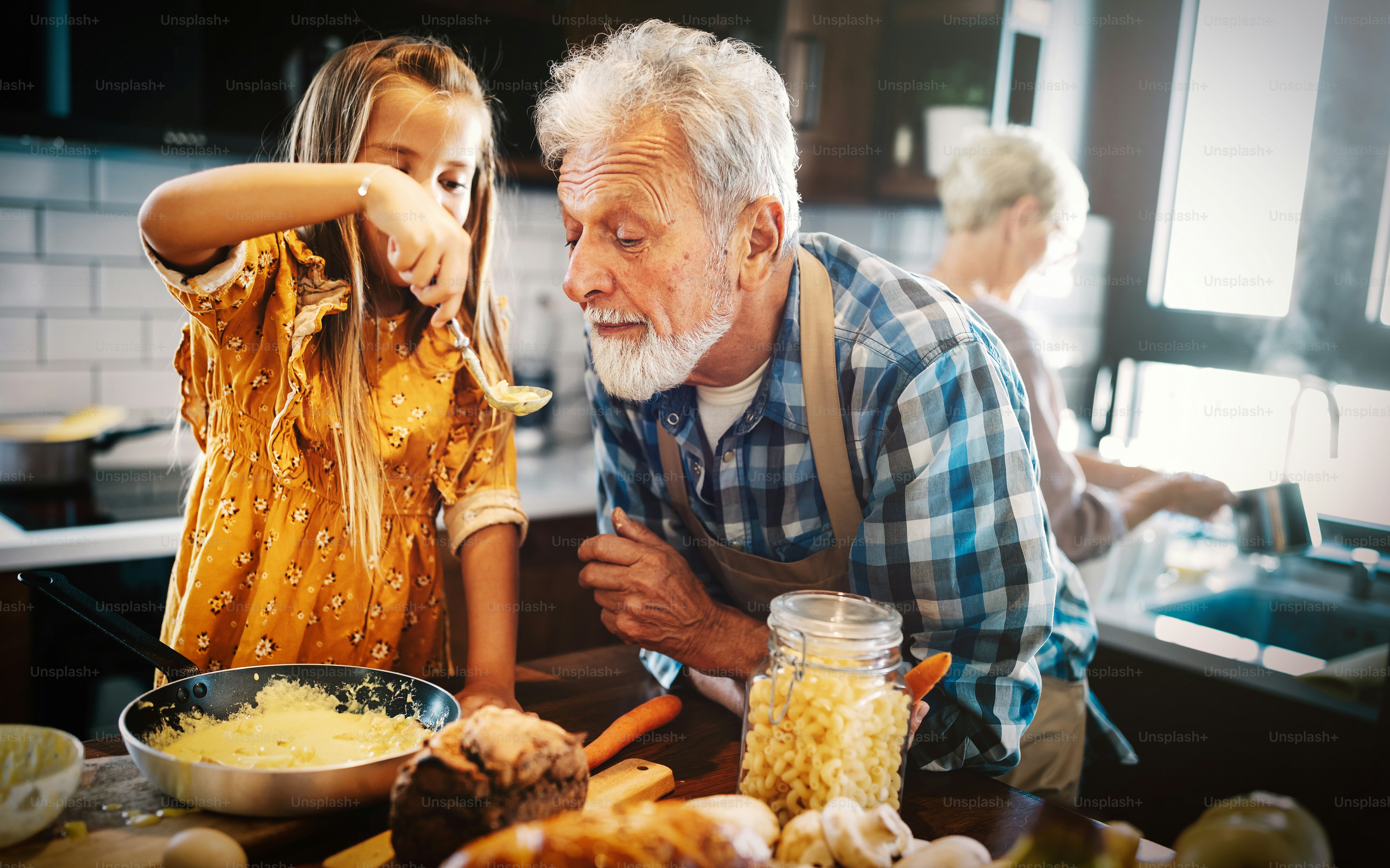 Happy young girl and her grandad cooking together in kitchen photo ...