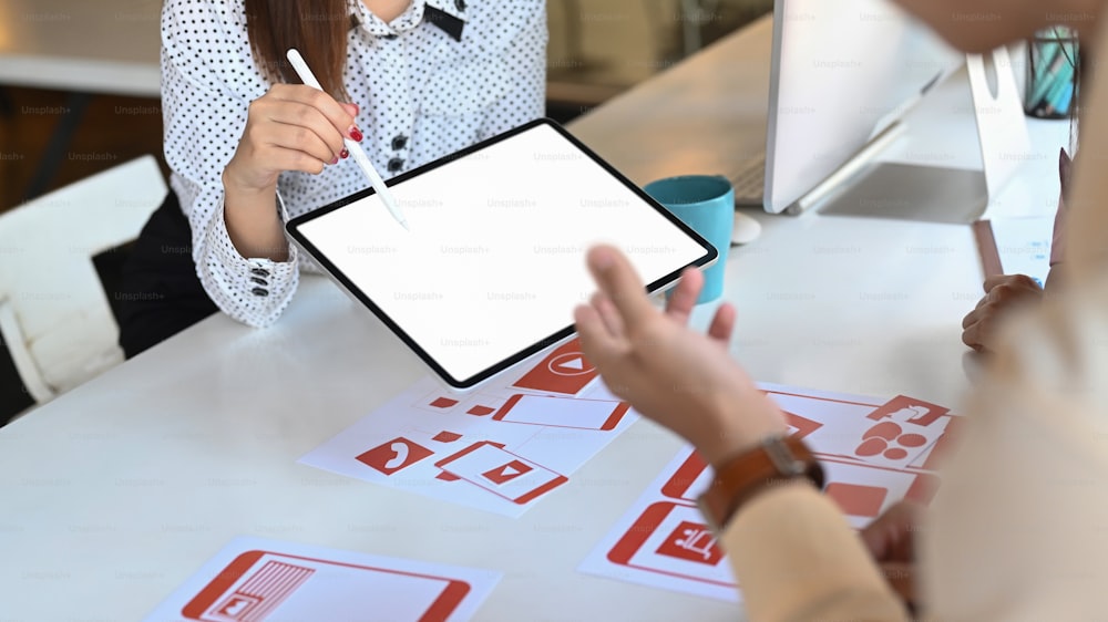 Ux developer and ui designer are using tablet and discussing ideas for ... Ux developer and ui designer are using tablet and discussing ideas for ...