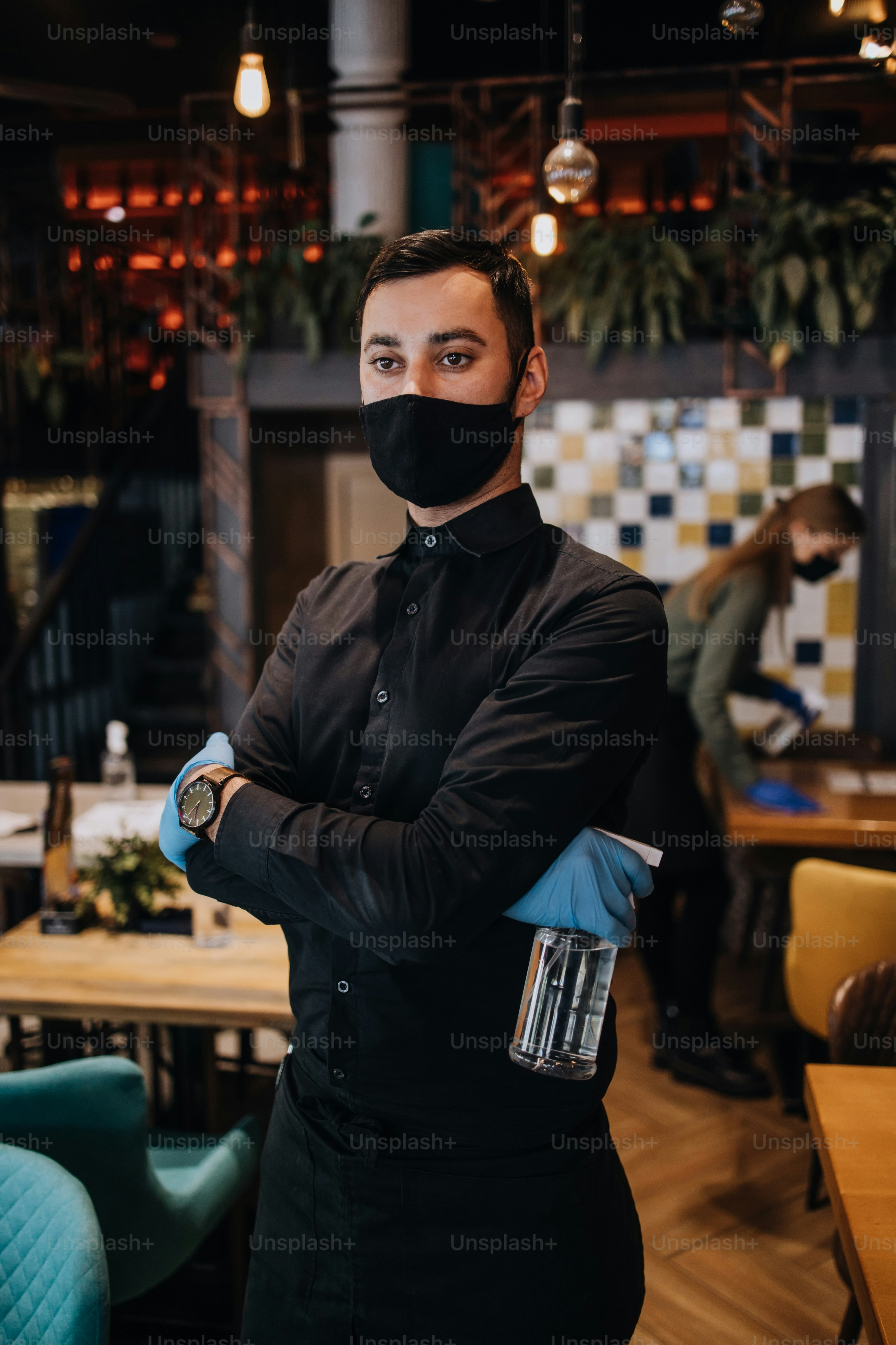 Portrait of a serious waiter standing in a nice restaurant. He wears a ...