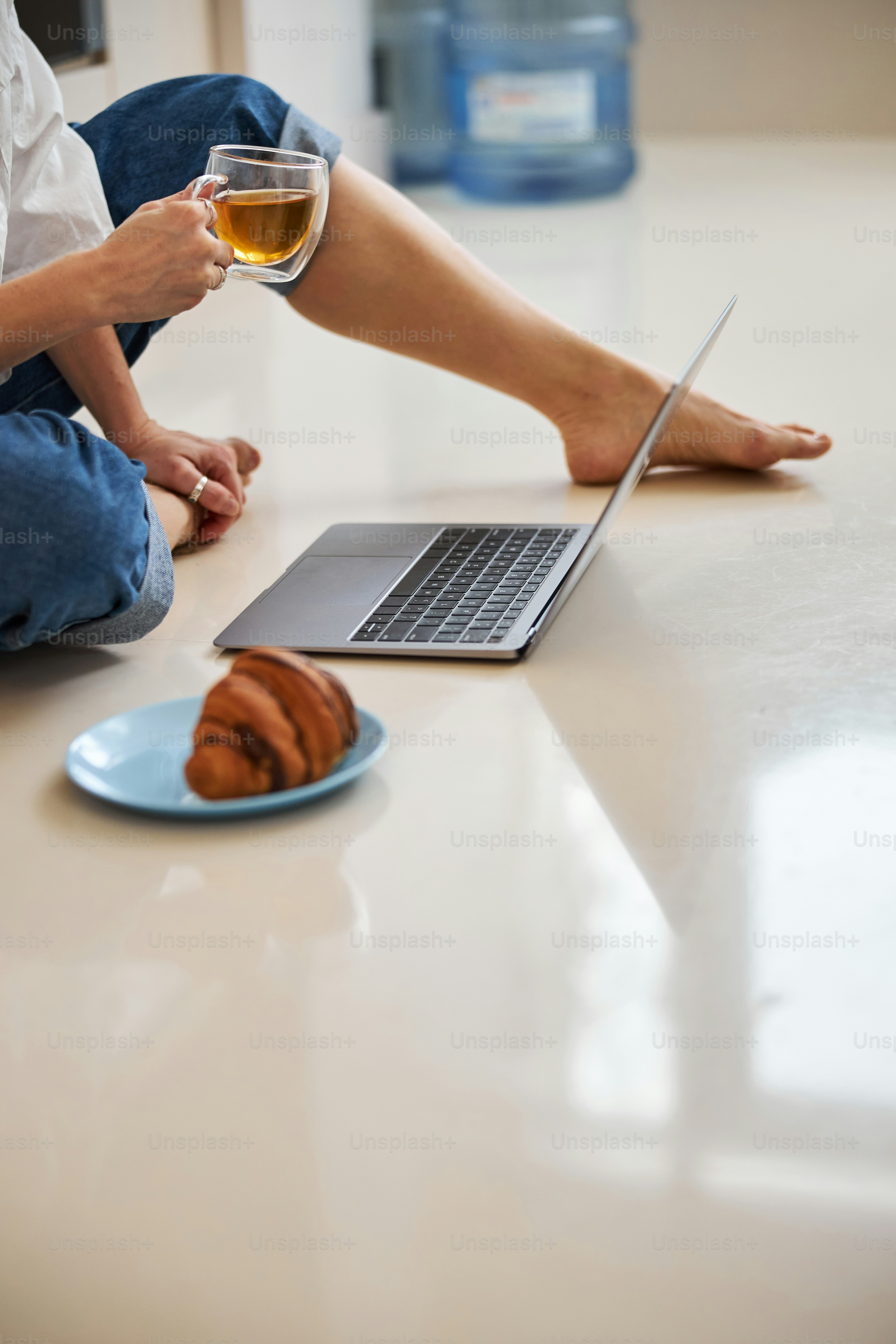 Close up of barefoot lady with cup of tea in her hand sitting on the ...
