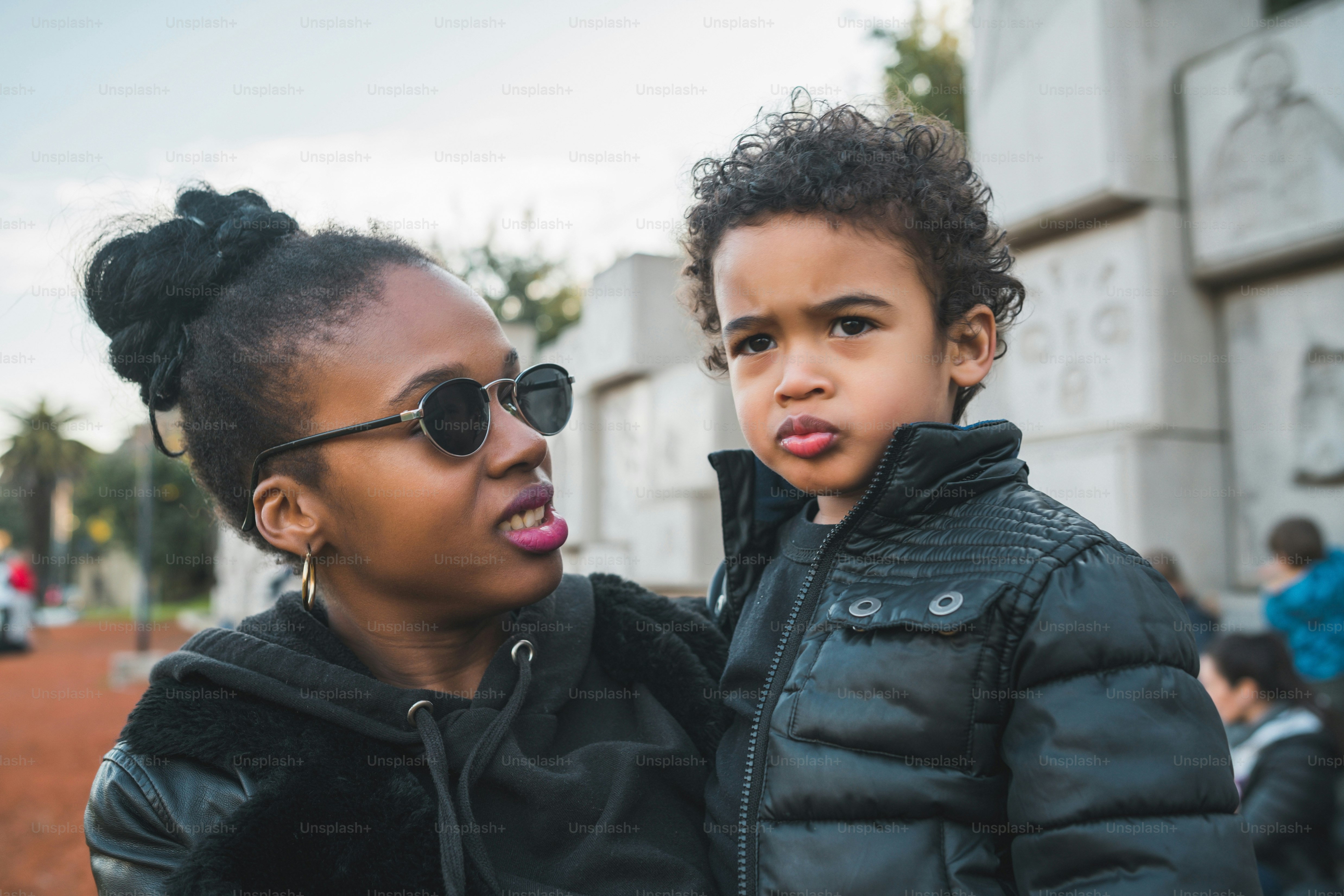 Portrait of an African american mother with his son standing outdoors ...