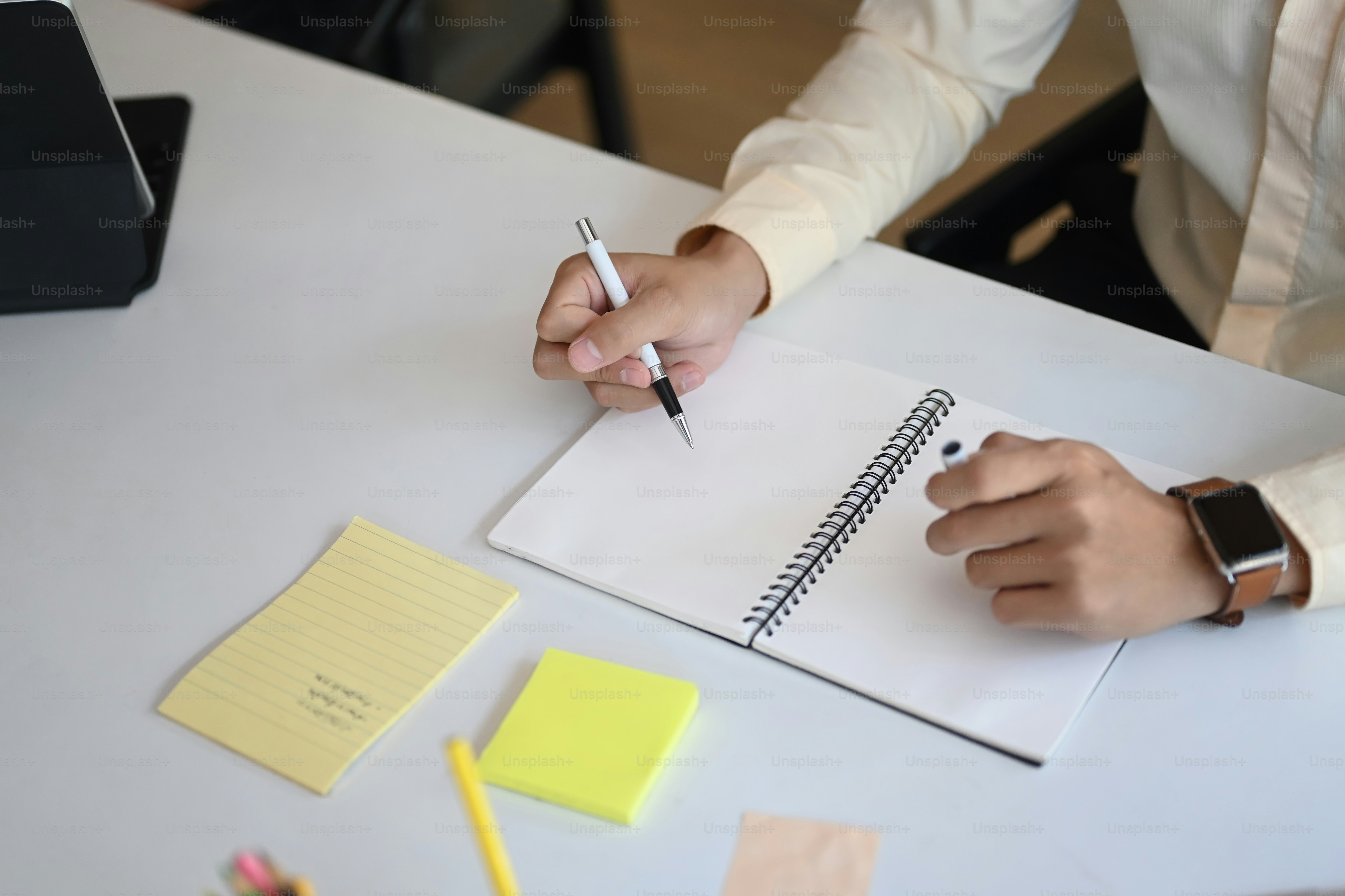 Cropped shot of businessman holding a pen taking note on notebook ...