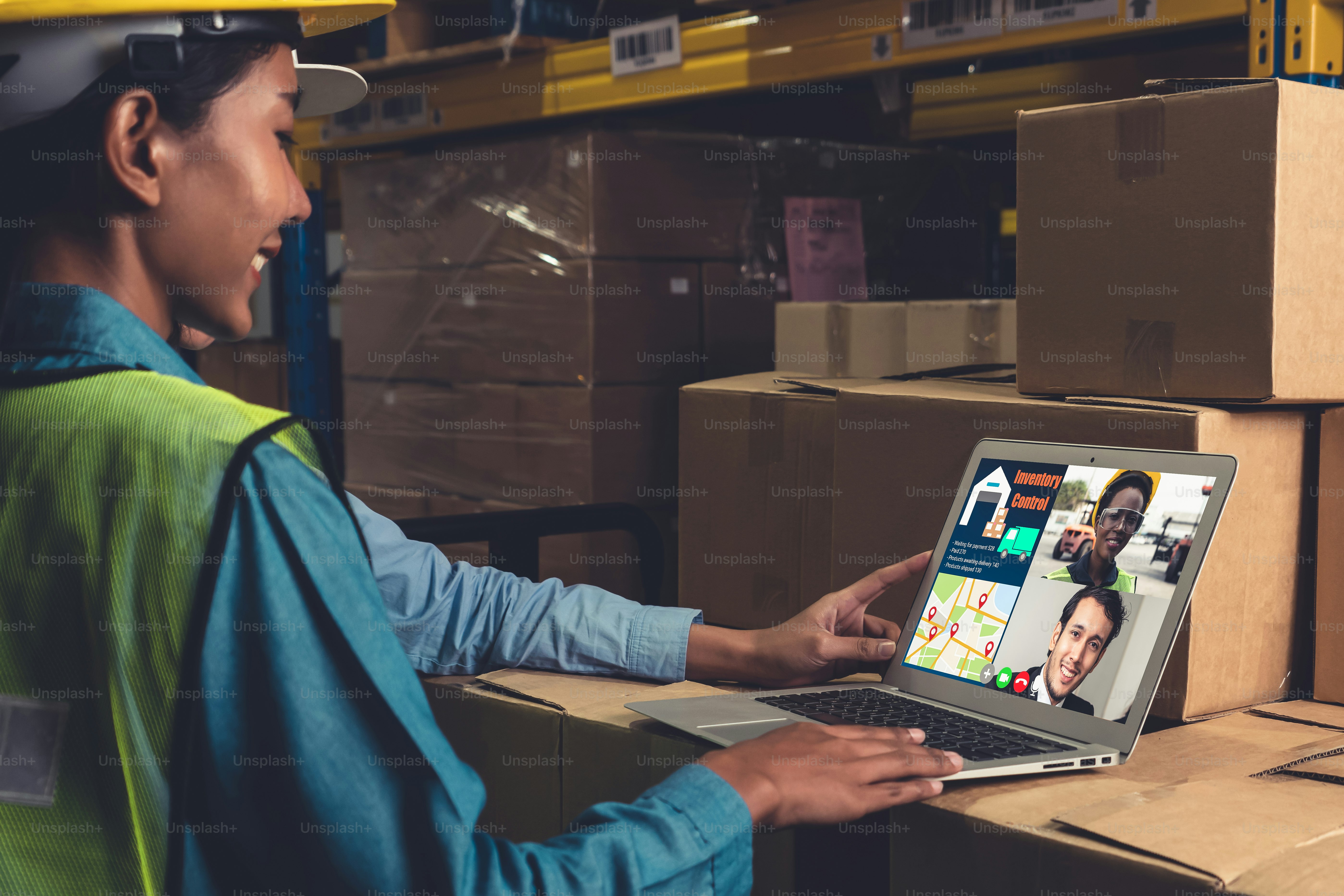 Warehouse staff talking on video call at computer screen in storage ...