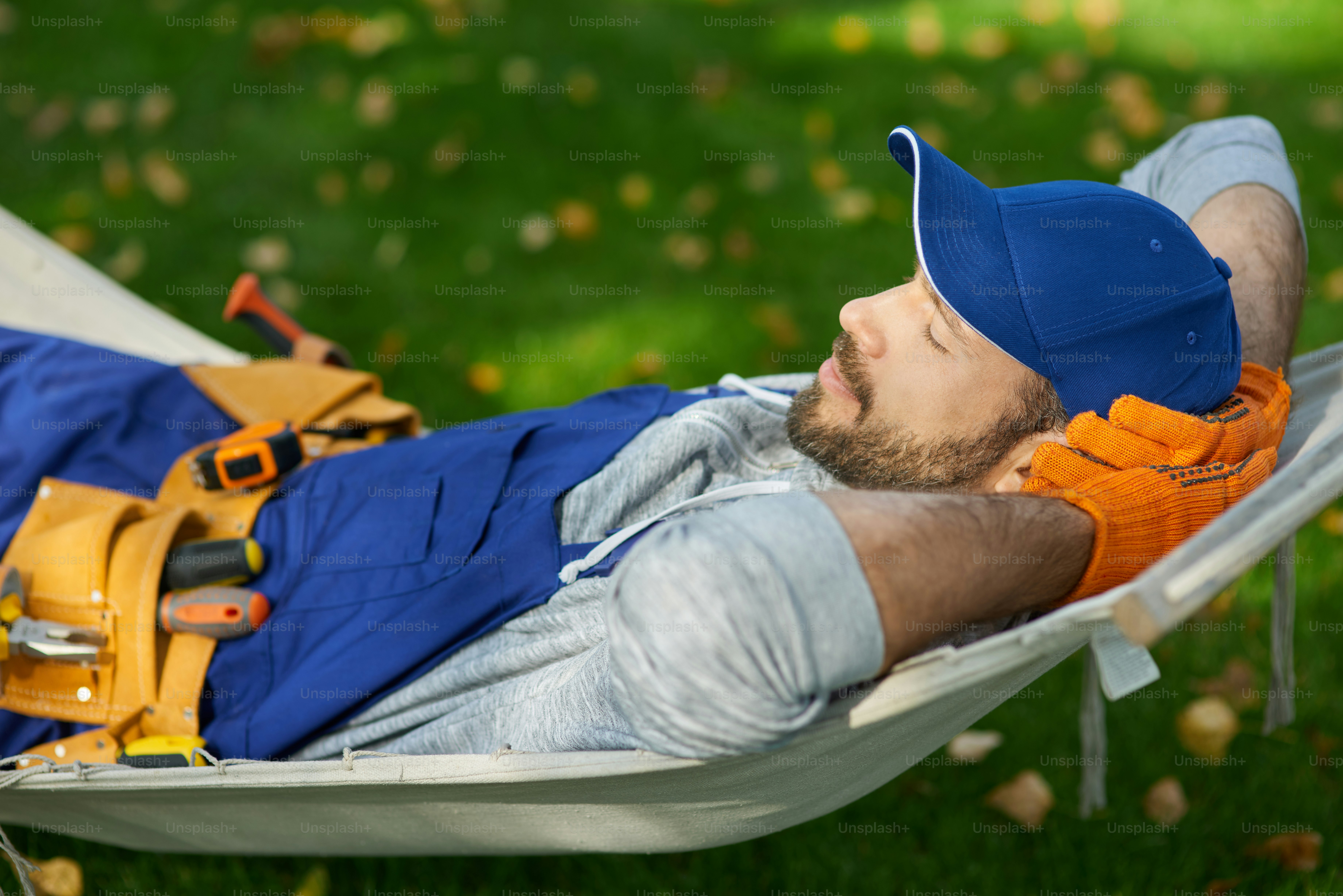 Peaceful young male builder wearing uniform taking a break, lying in a ...