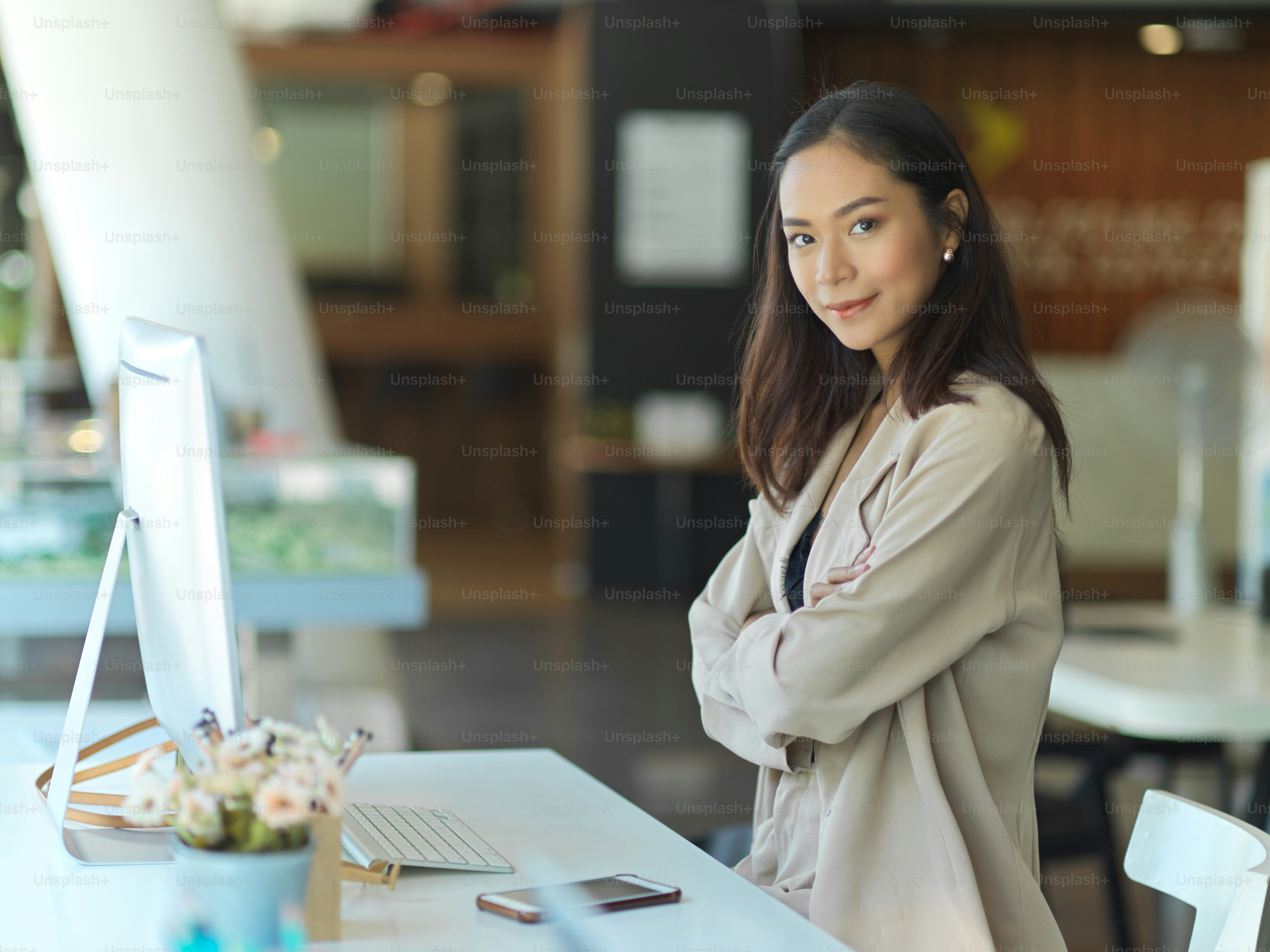 Portrait of female office worker smiling to camera while sitting at ...