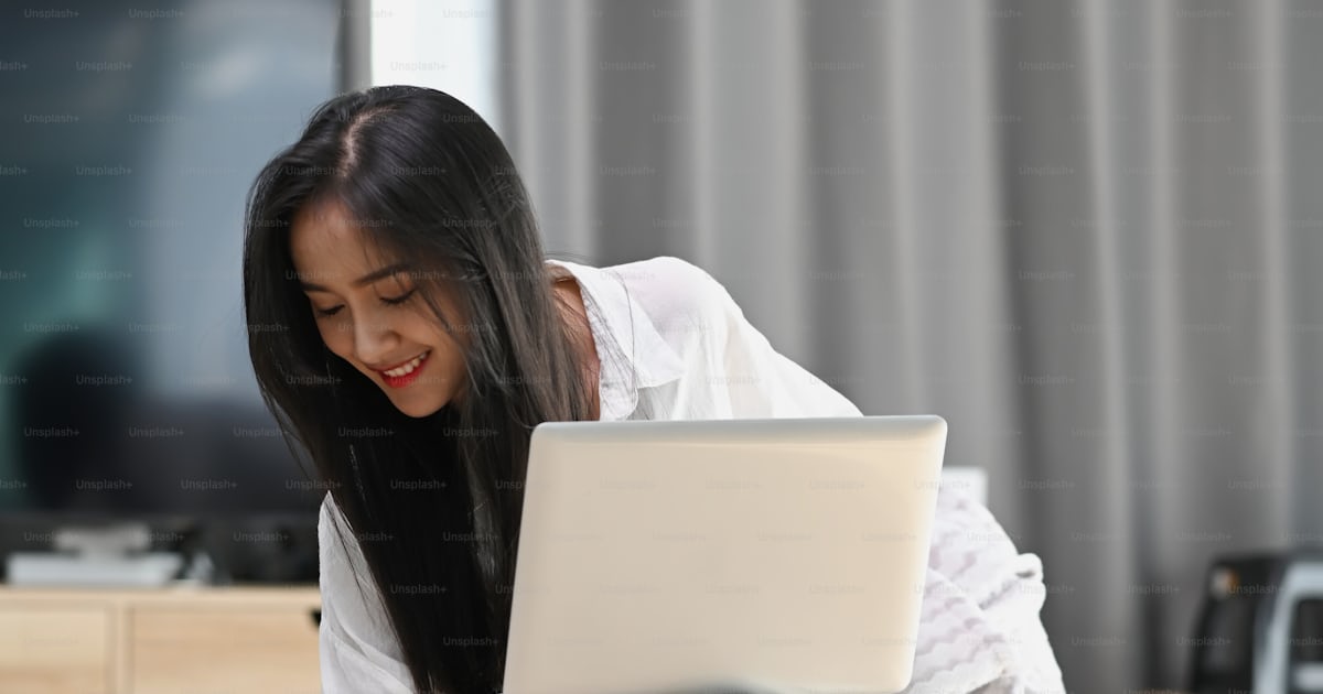 노트북 컴퓨터가 소파에 앉아 있고 로봇 청소기가 집에서 방을 청소하는 행복한 여자 사진 Unsplash의 위생 이미지