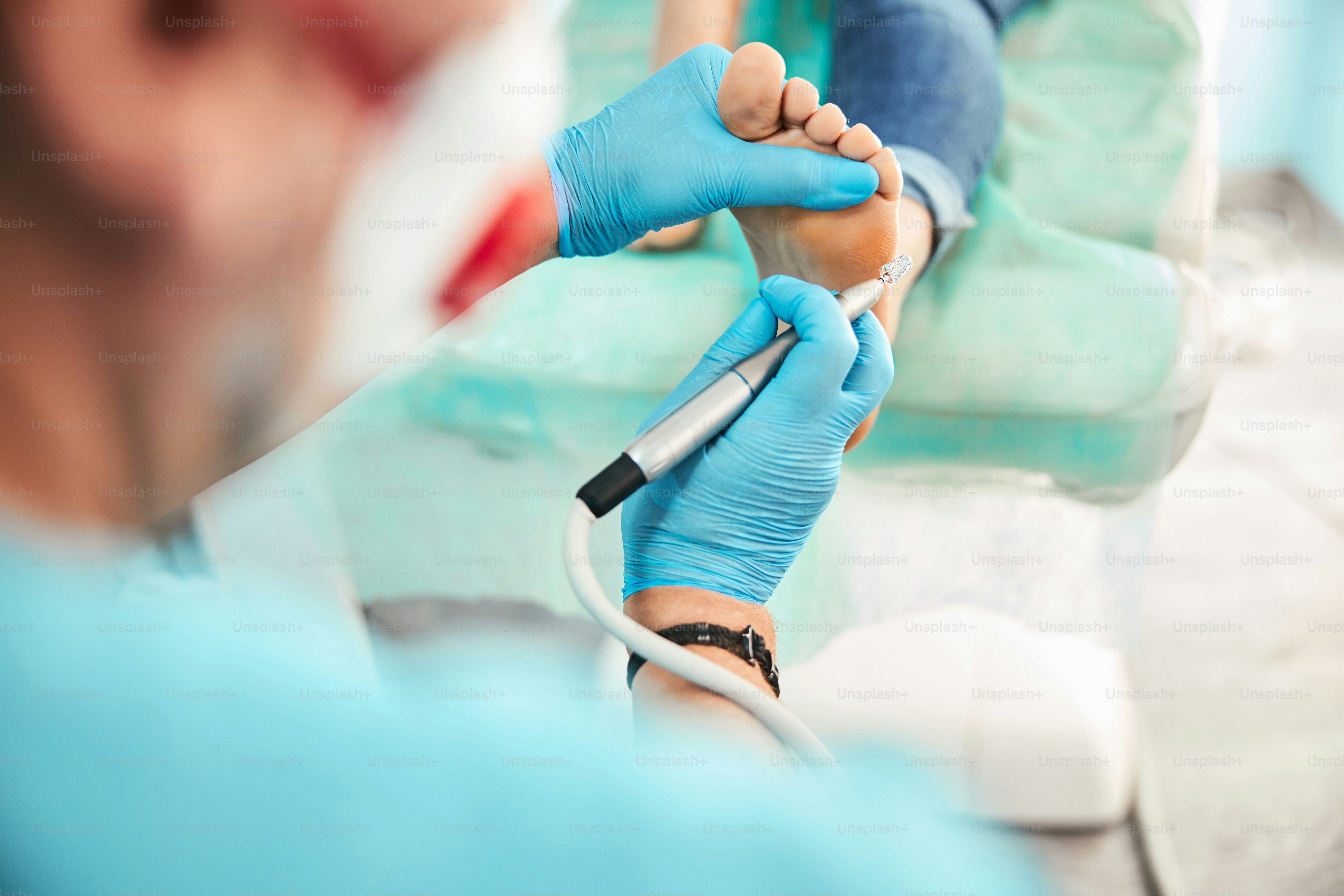 Close up portrait of chiropodist taking care of foot while removing ...