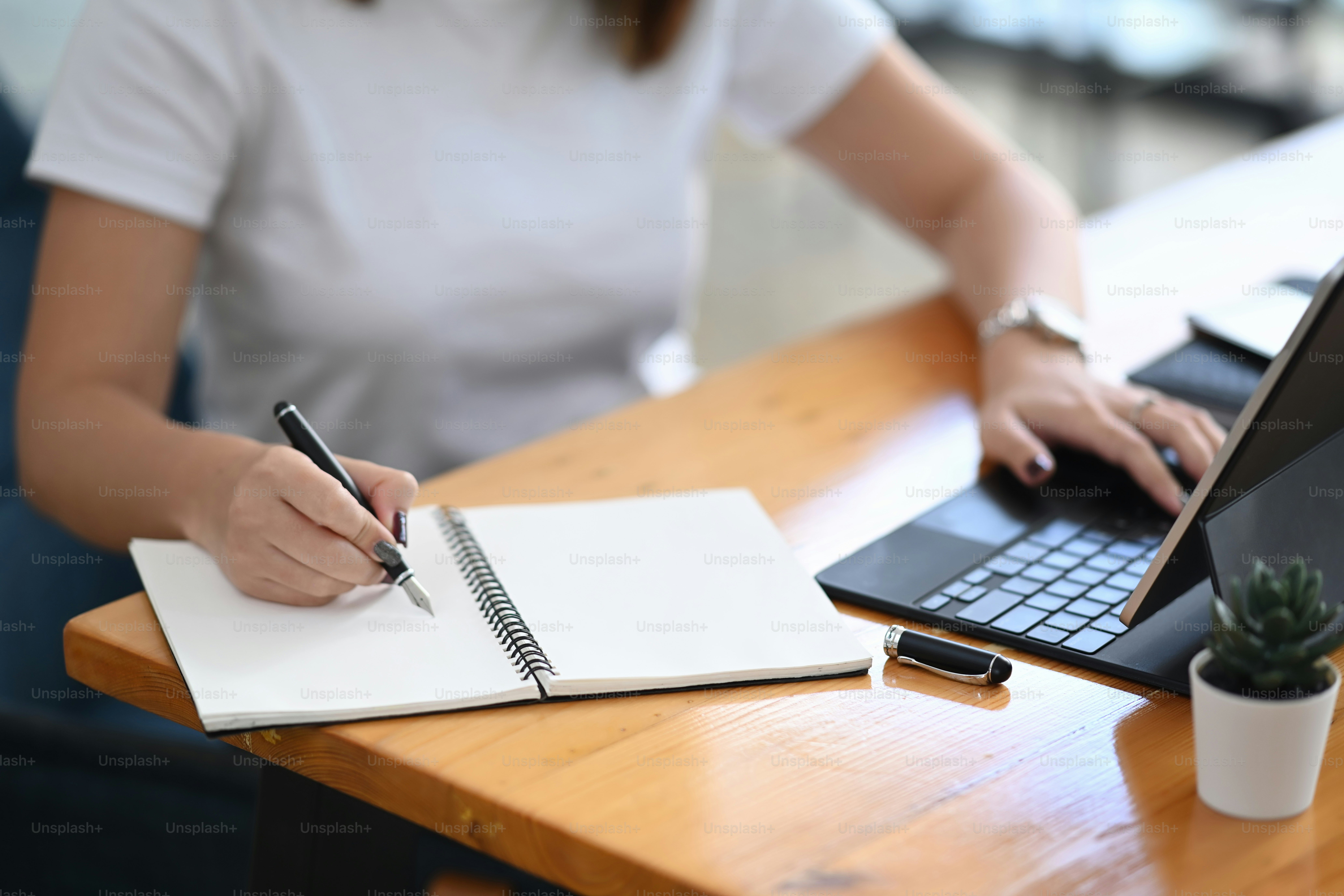 Close up view of female using computer tablet and making notes or ...