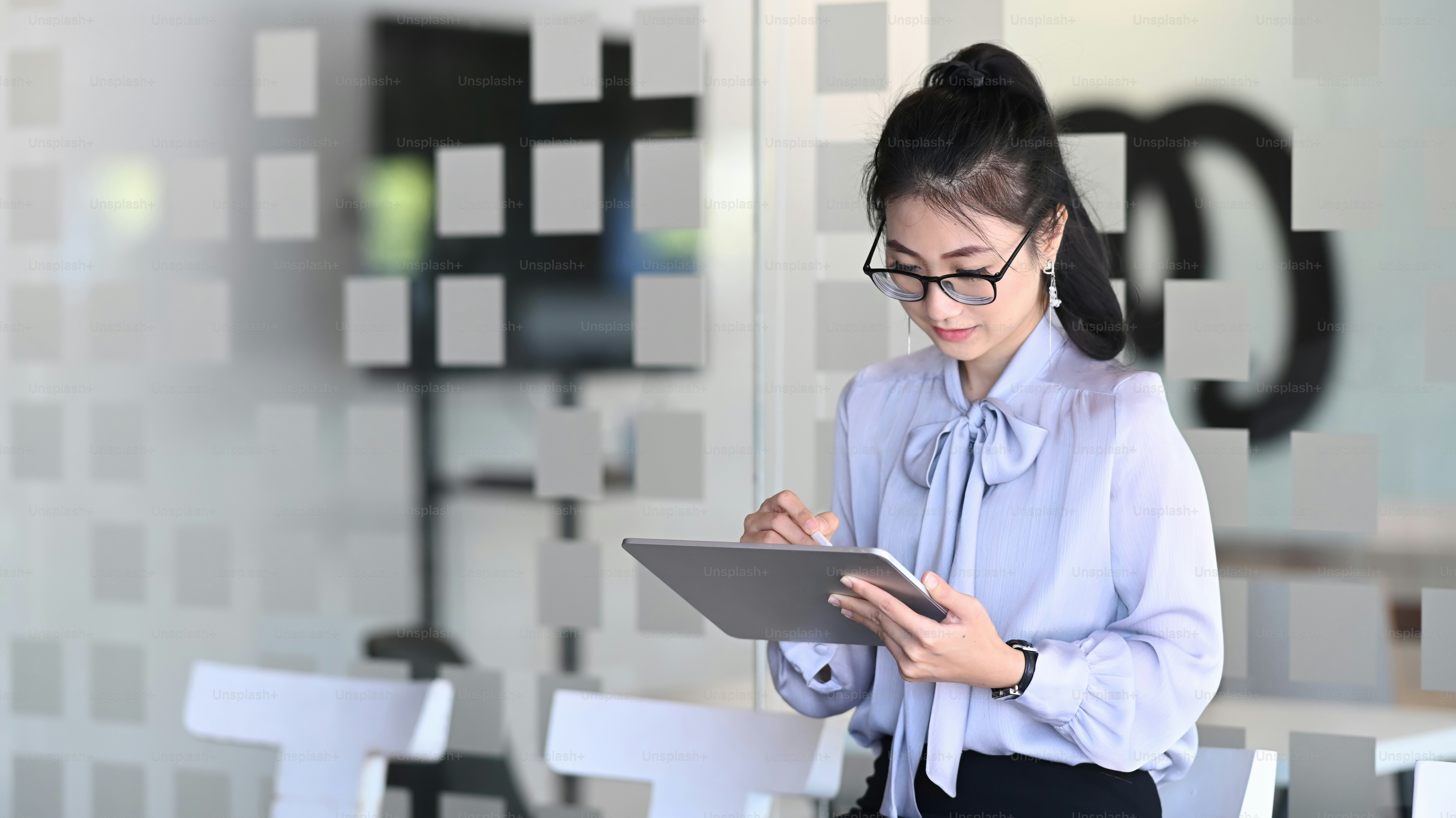 Young female office worker in glasses sitting in office and concentrate ...