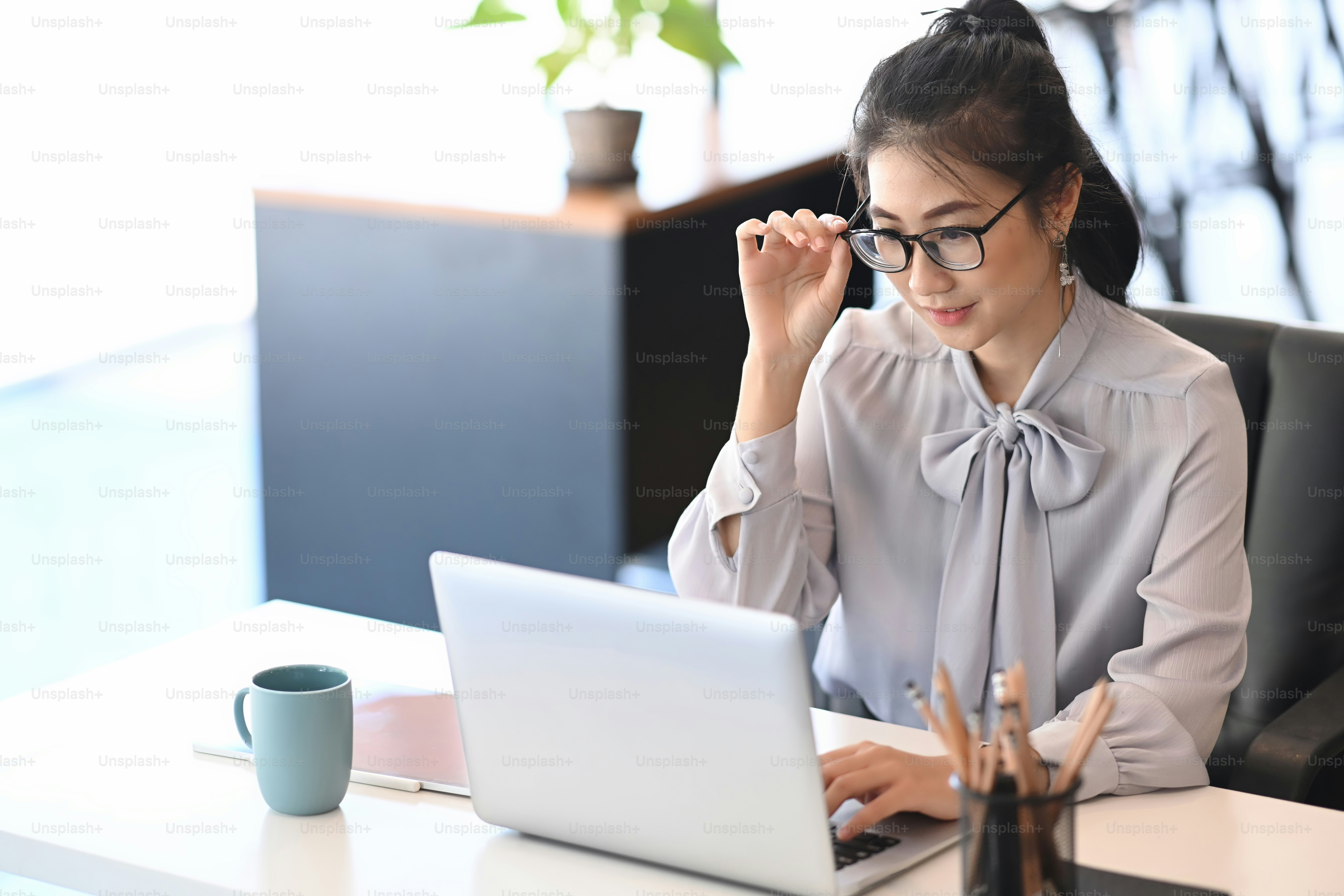 Thoughtful business woman in eyeglass working with computer laptop at ...