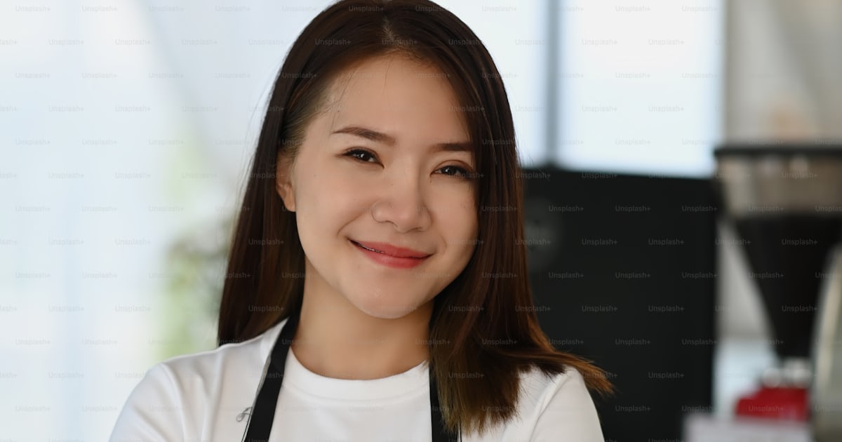 앞치마를 두른 쾌활한 여성 바리스타들이 카페 카운터에 서서 커피 메이킹 액세서리를 들고 있는 초상화 사진 Unsplash의