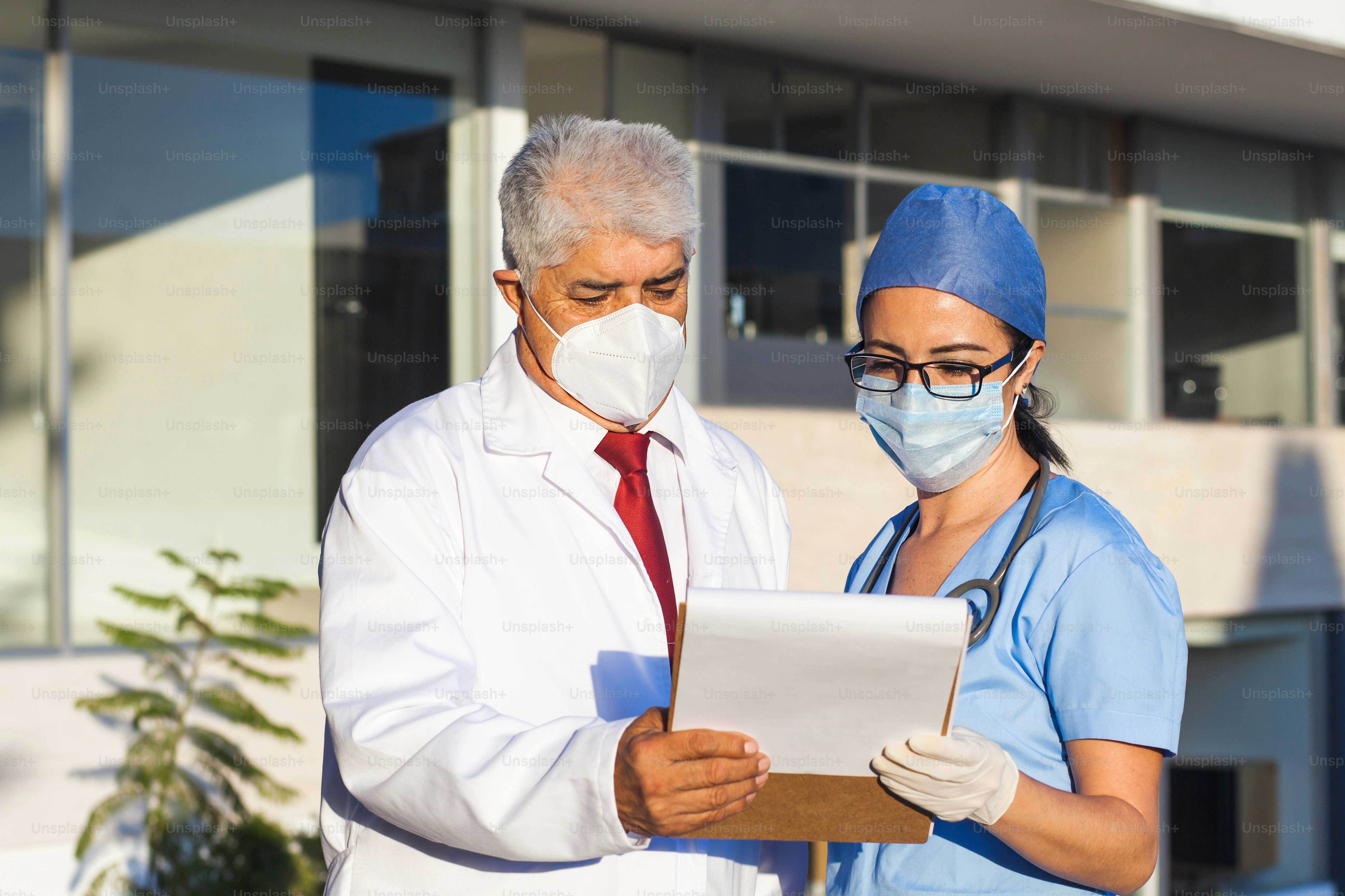 Latin team of medical doctors are looking at camera and smiling while ...