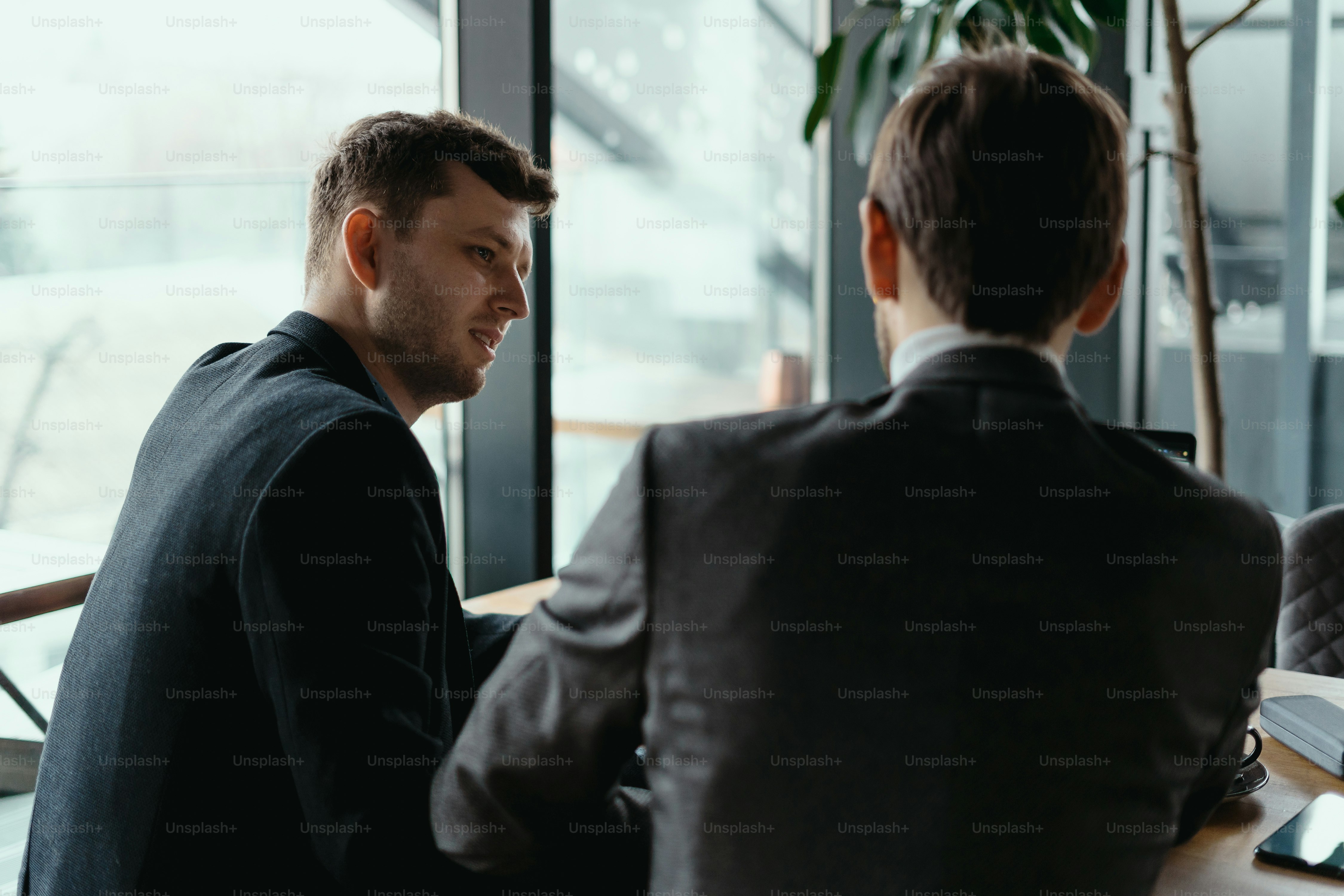 Focused businessman listening to business partner talking during ...