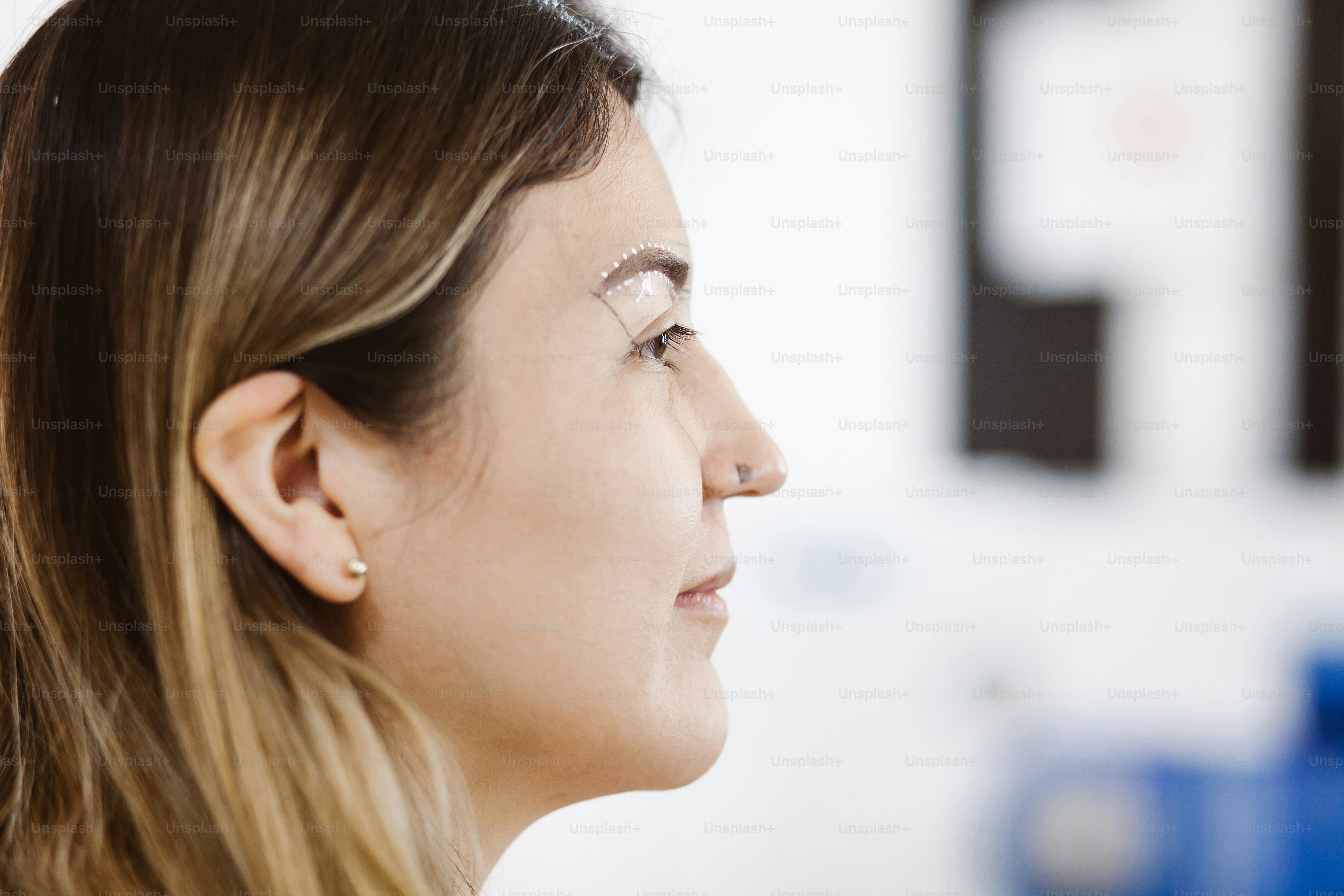 Latin Cosmetologist preparing to mexican woman for eyebrow permanent ...