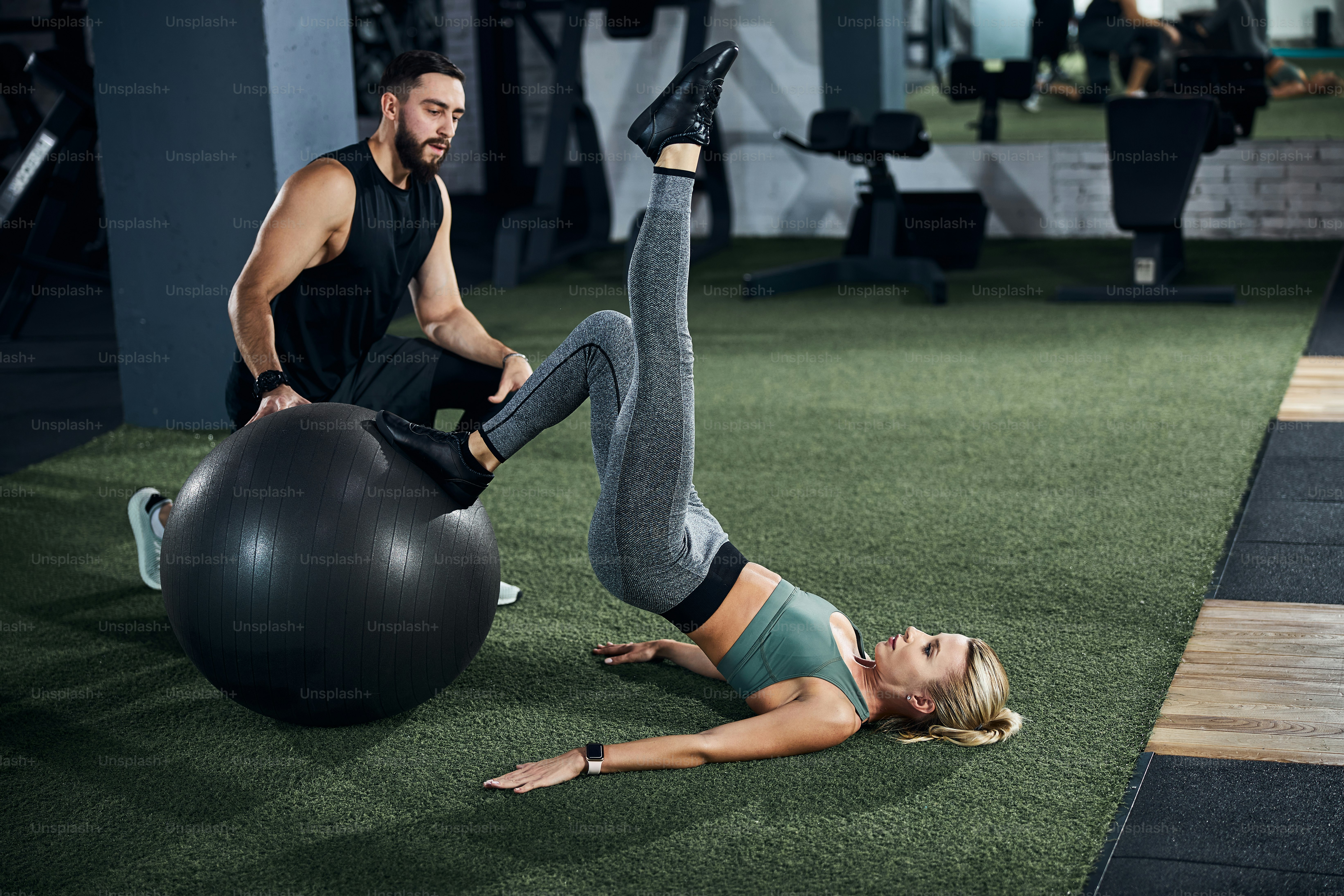 Person following the instructions of a gym coach and pulling her leg ...