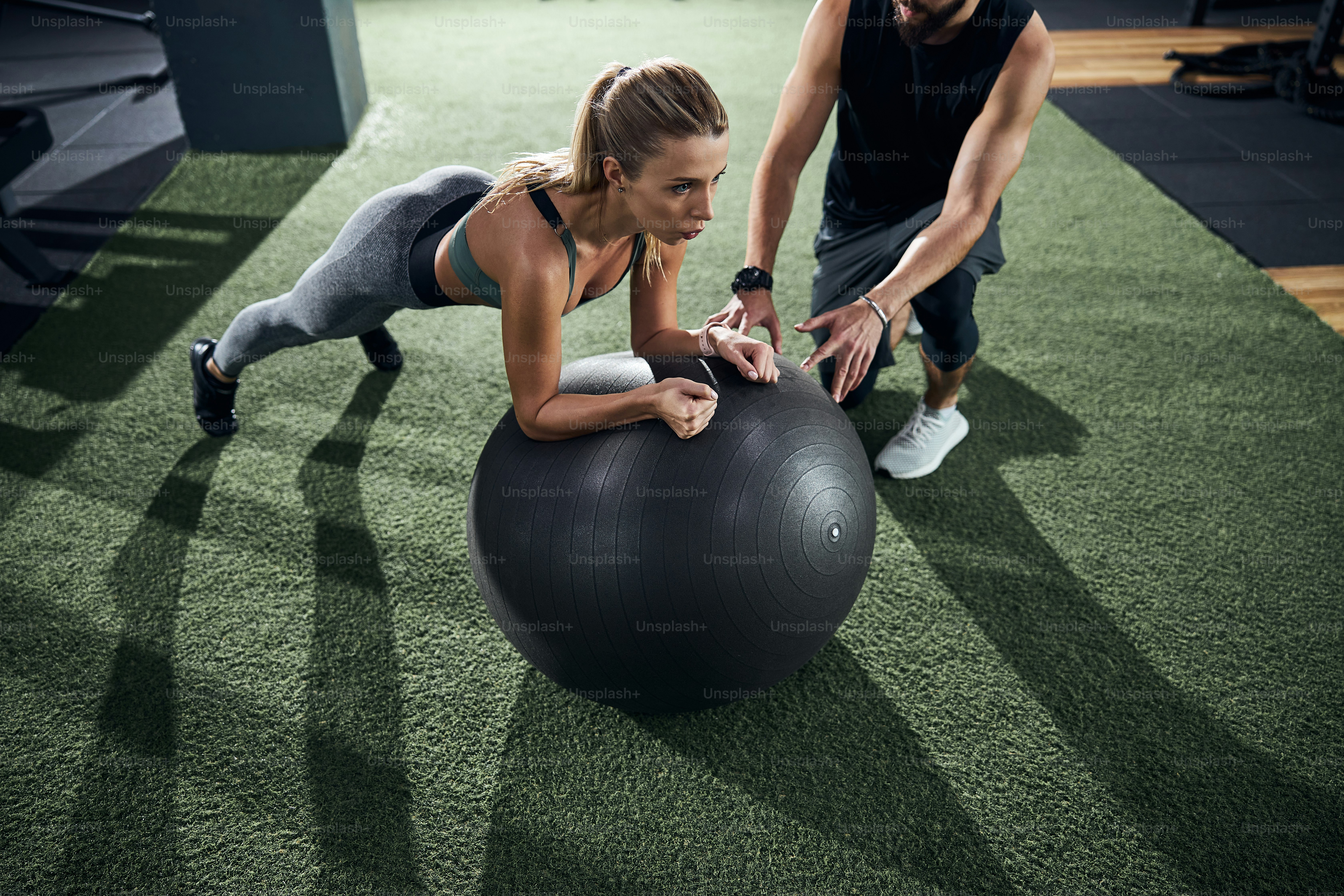 Male instructor straightening the back position of a gym visitor for a ...