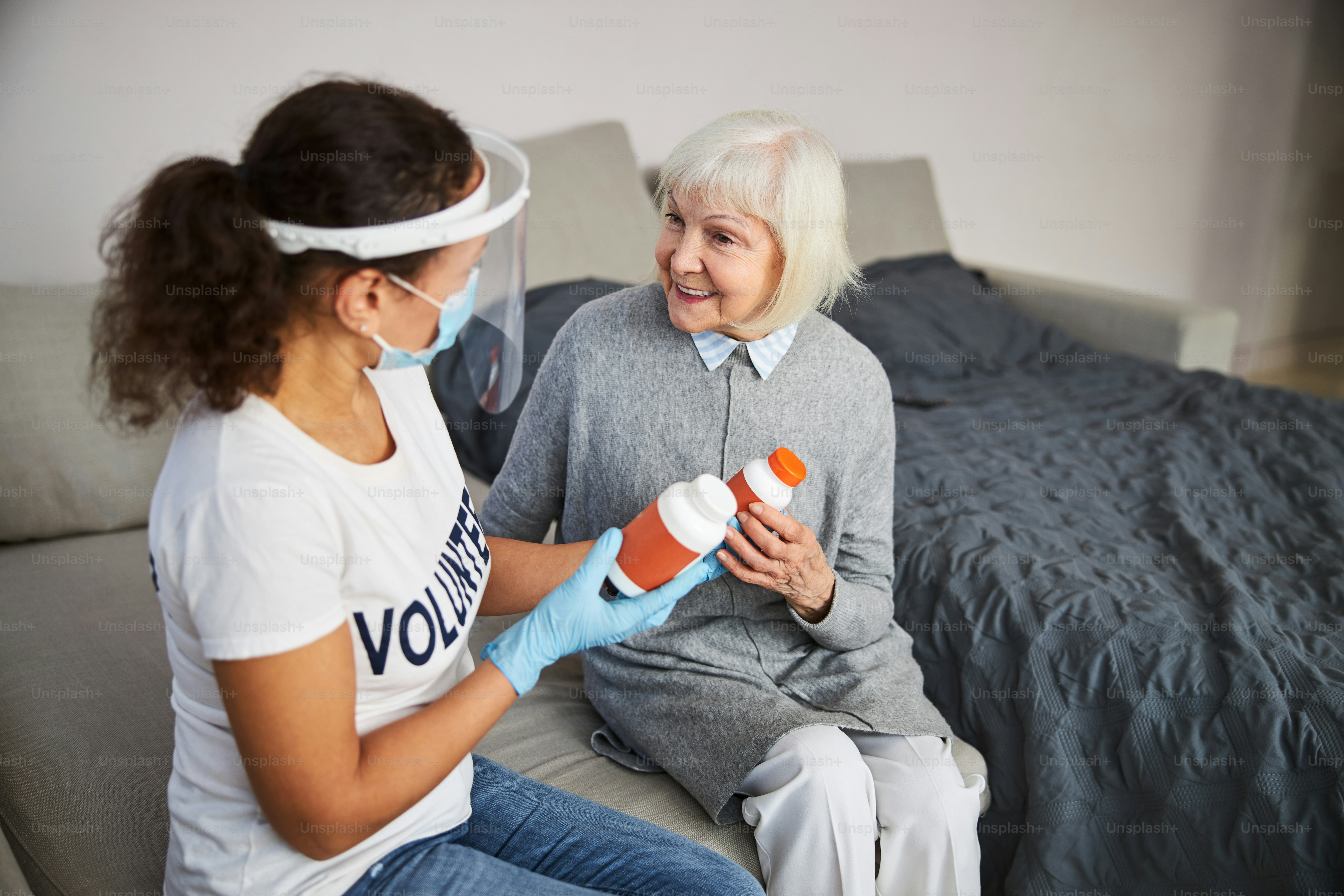 Care worker giving two variants of medicine to an aging person with a ...