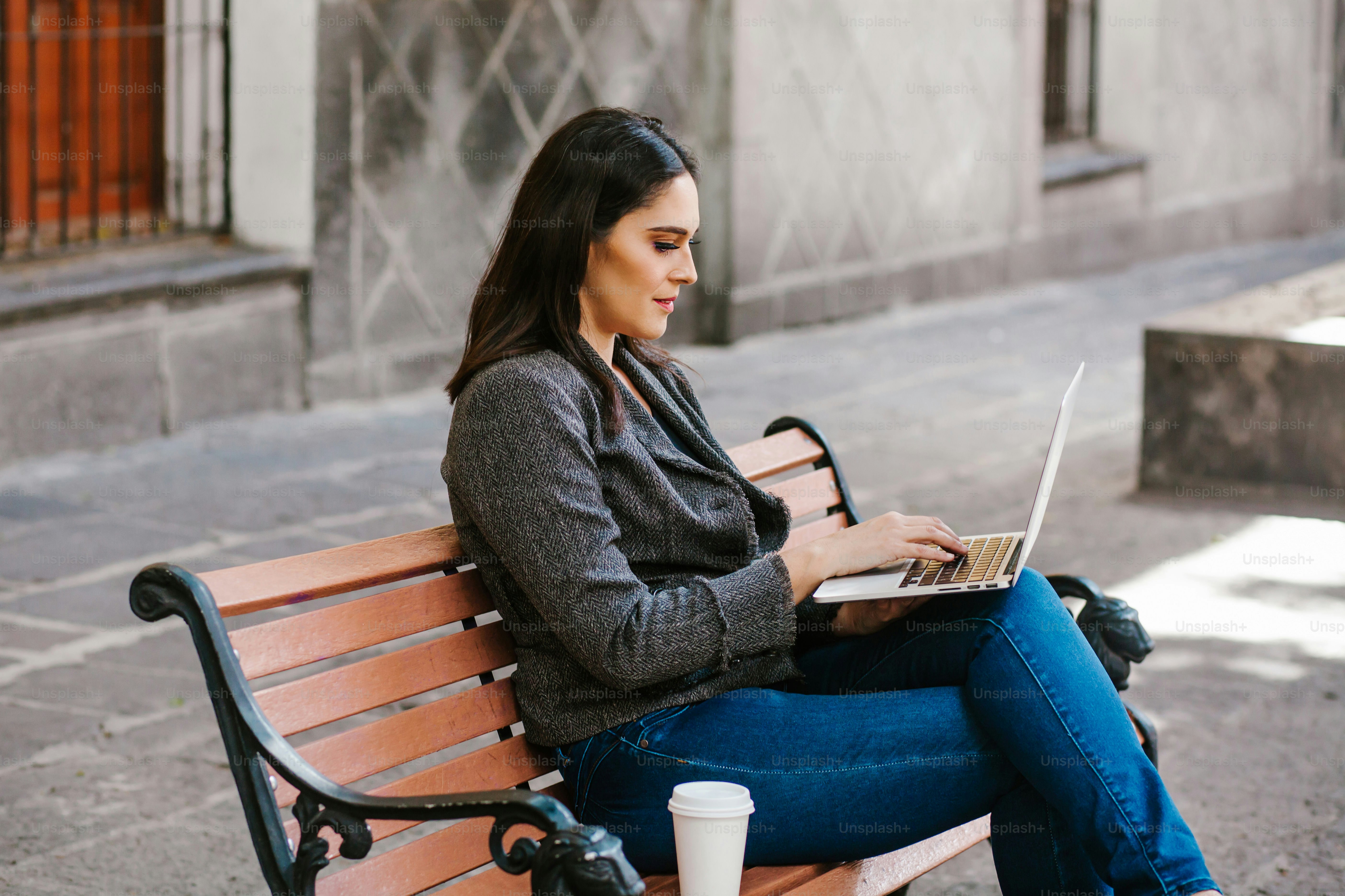 Mexican woman working with her laptop in a park bench in a colonial ...