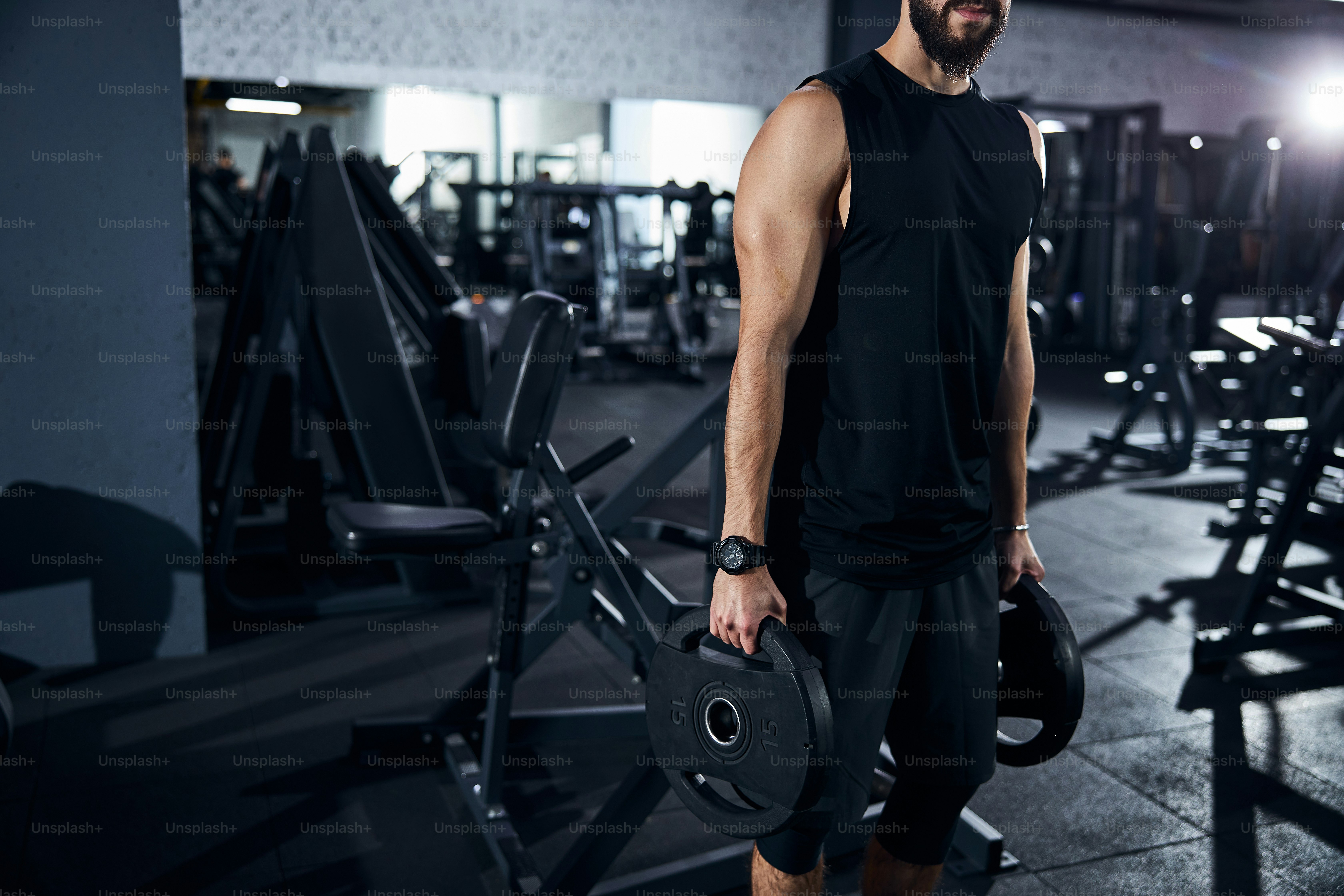 Adult male standing near many training machines with circular weights ...