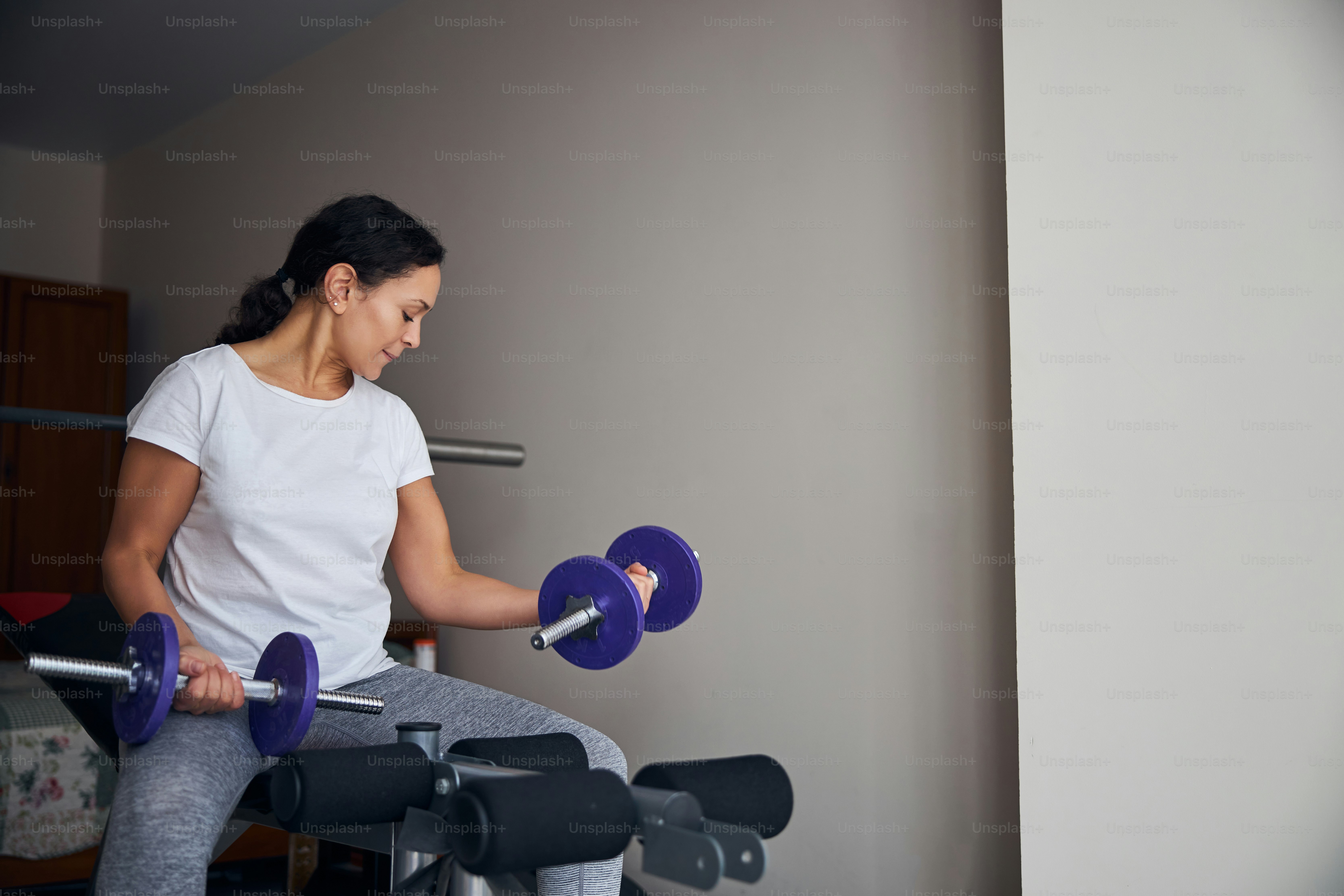 Strong female athlete doing the concentration curls on the workout ...