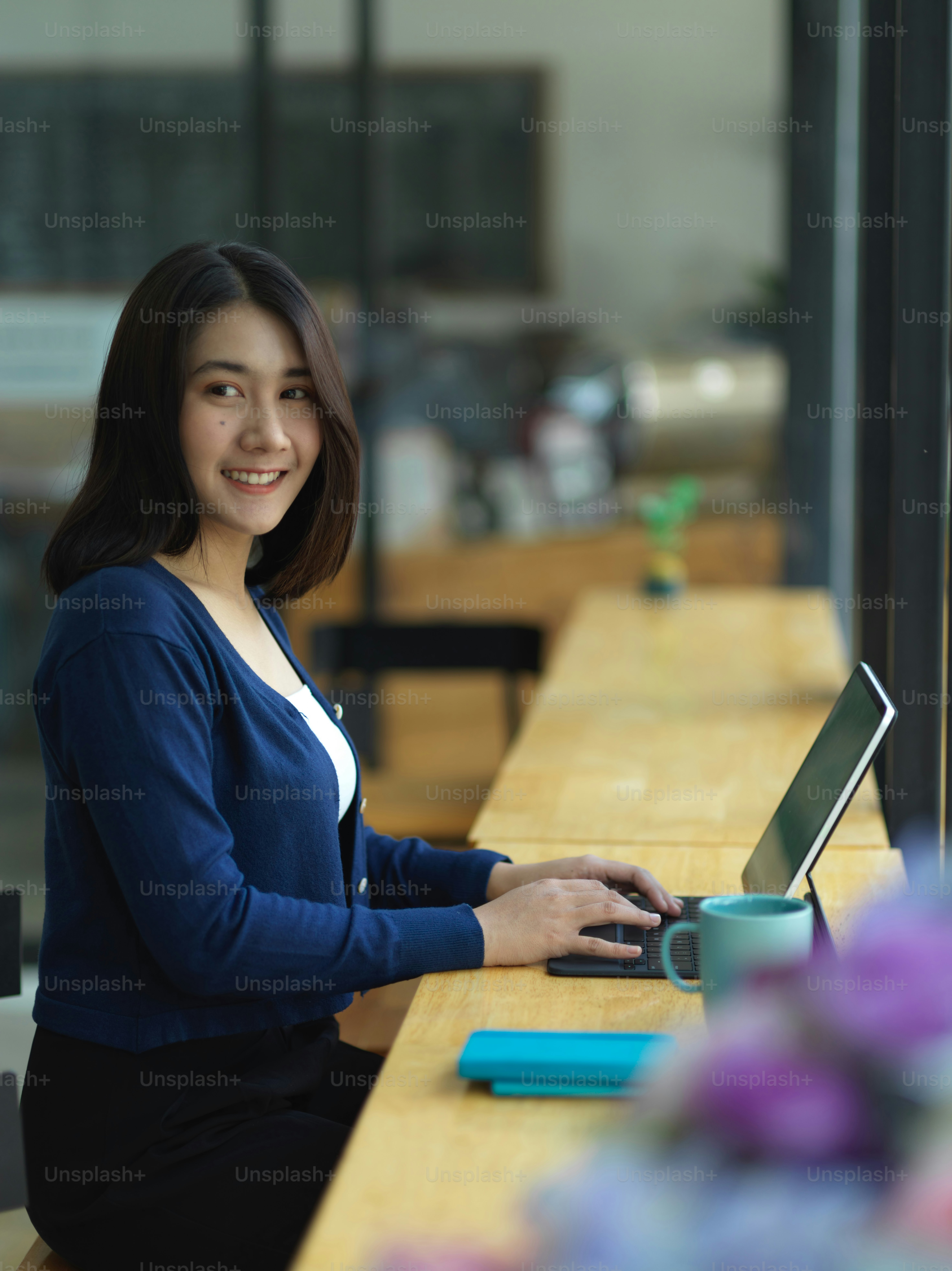 Portrait of female university student smiling to camera while doing ...