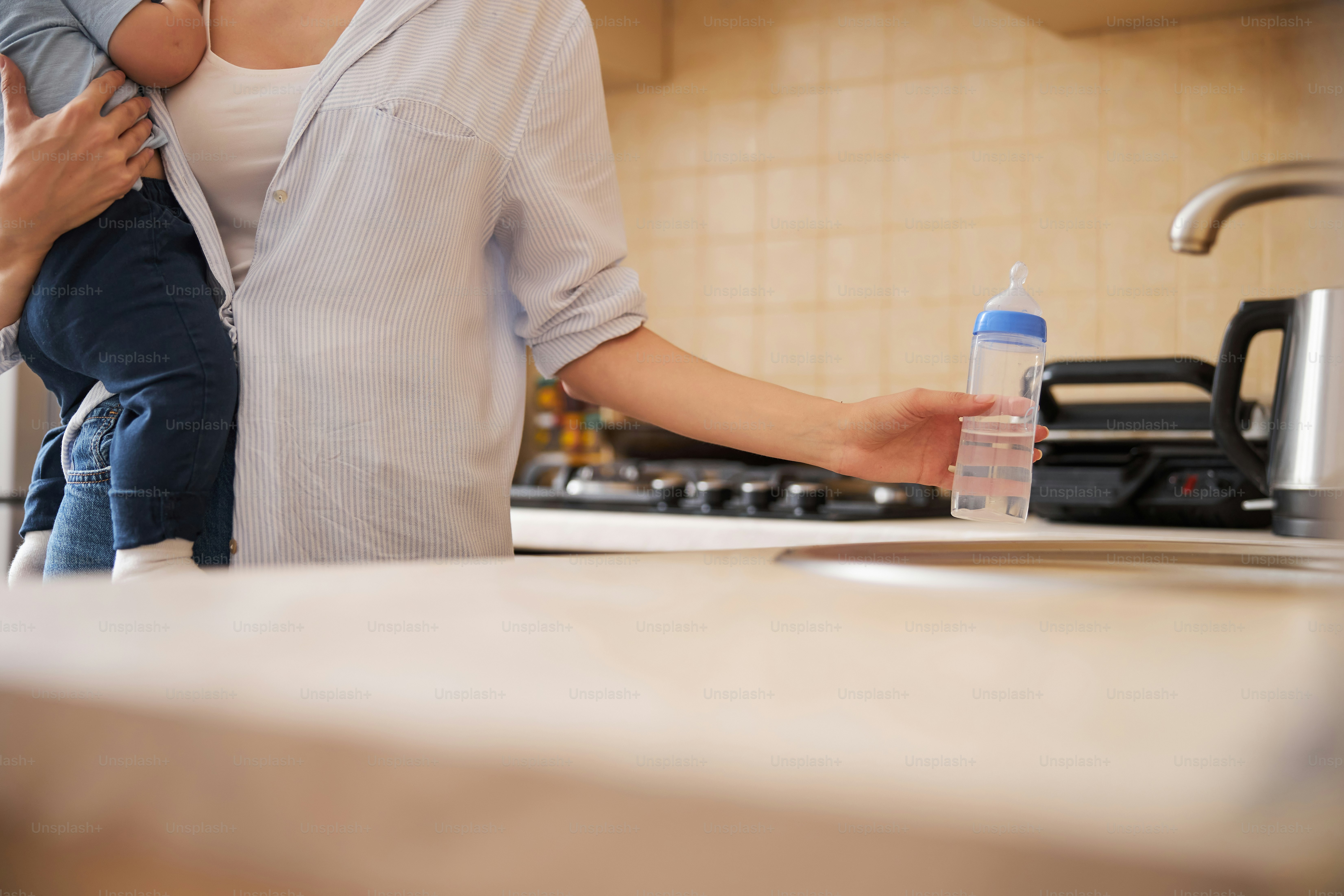 Madre responsable revisa el biberón con agua tibia antes de dárselo a ...