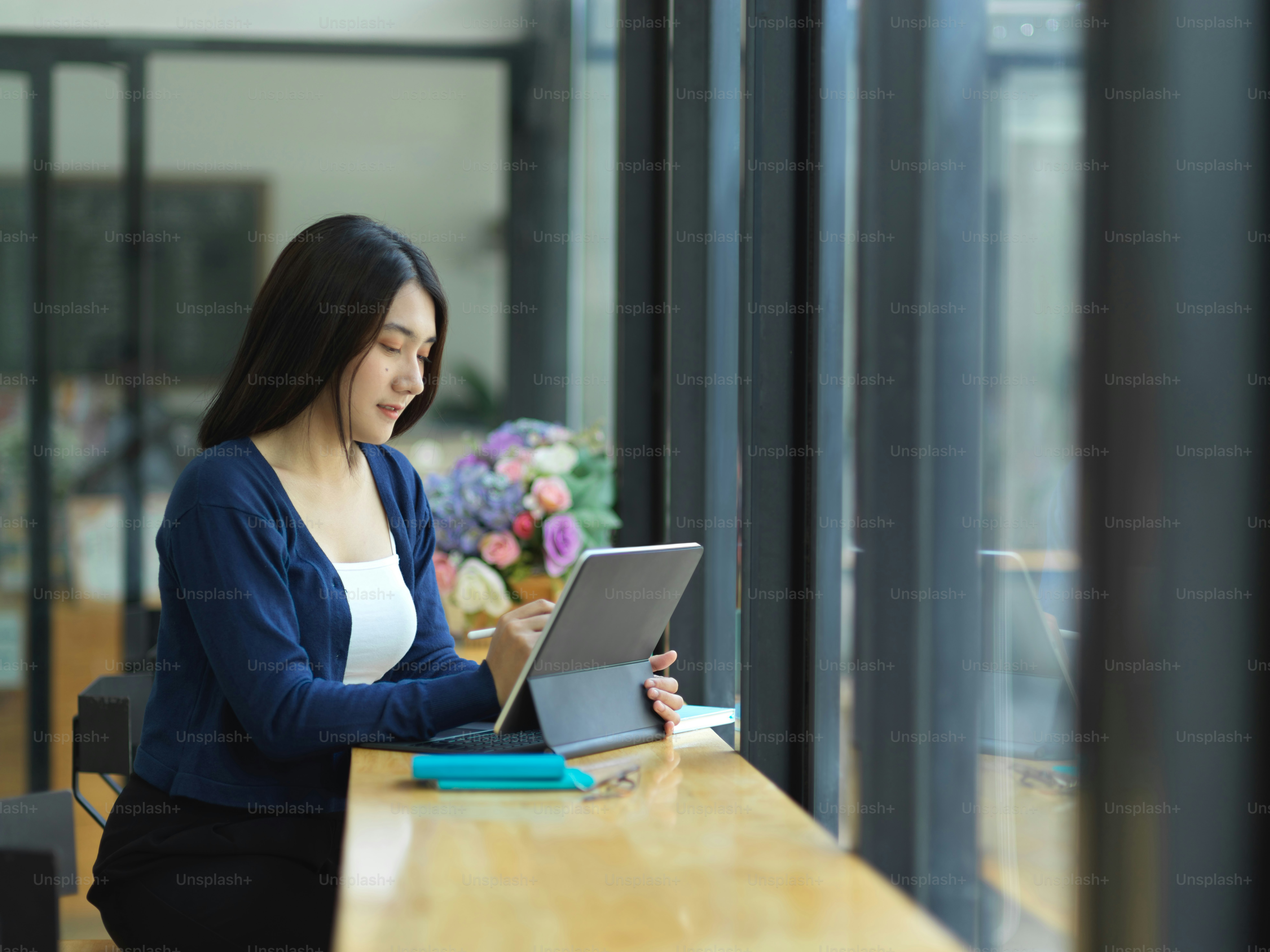 Side view of female university student doing homework with digital ...