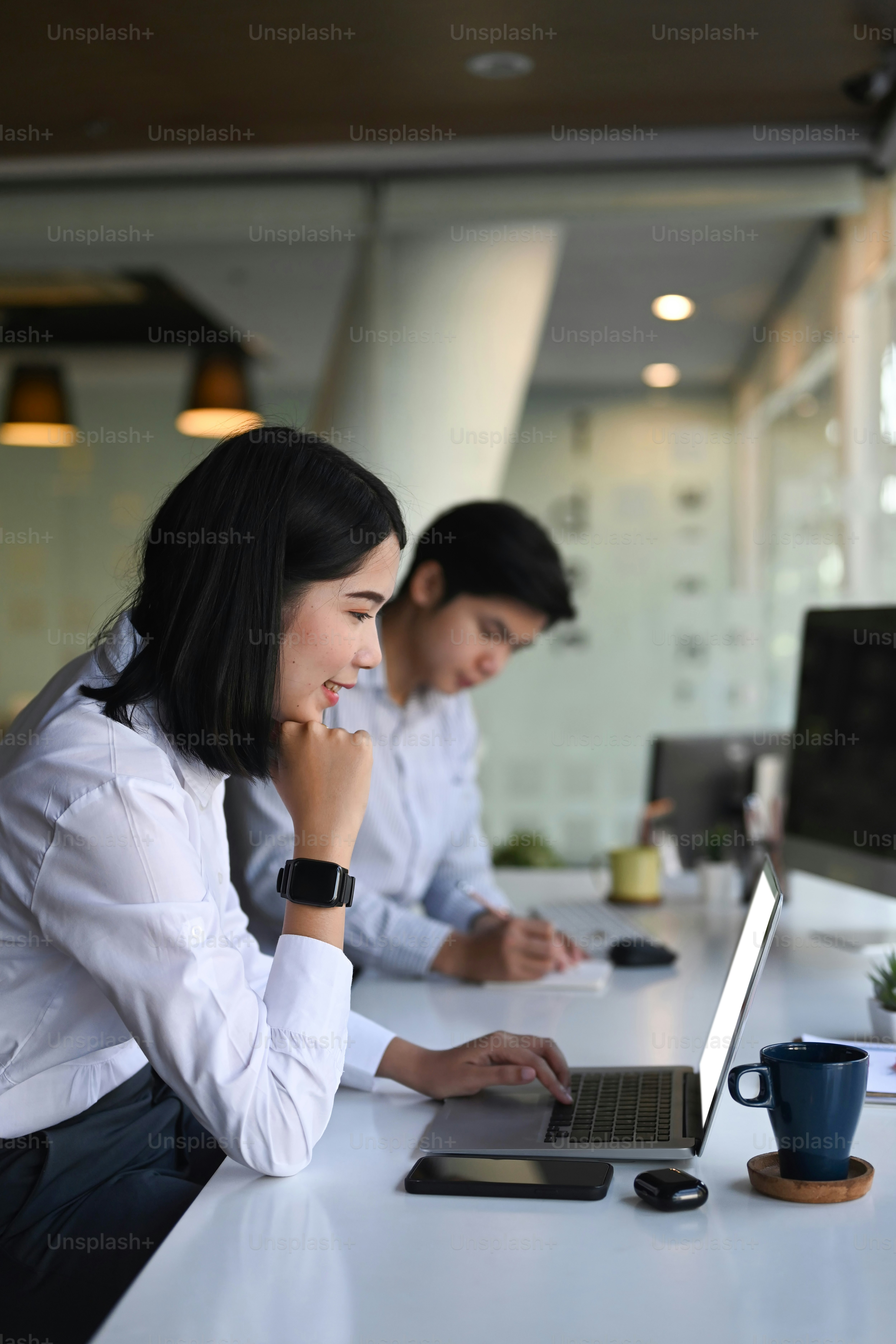 Sideview of businesswoman working with laptop computer and sitting with ...