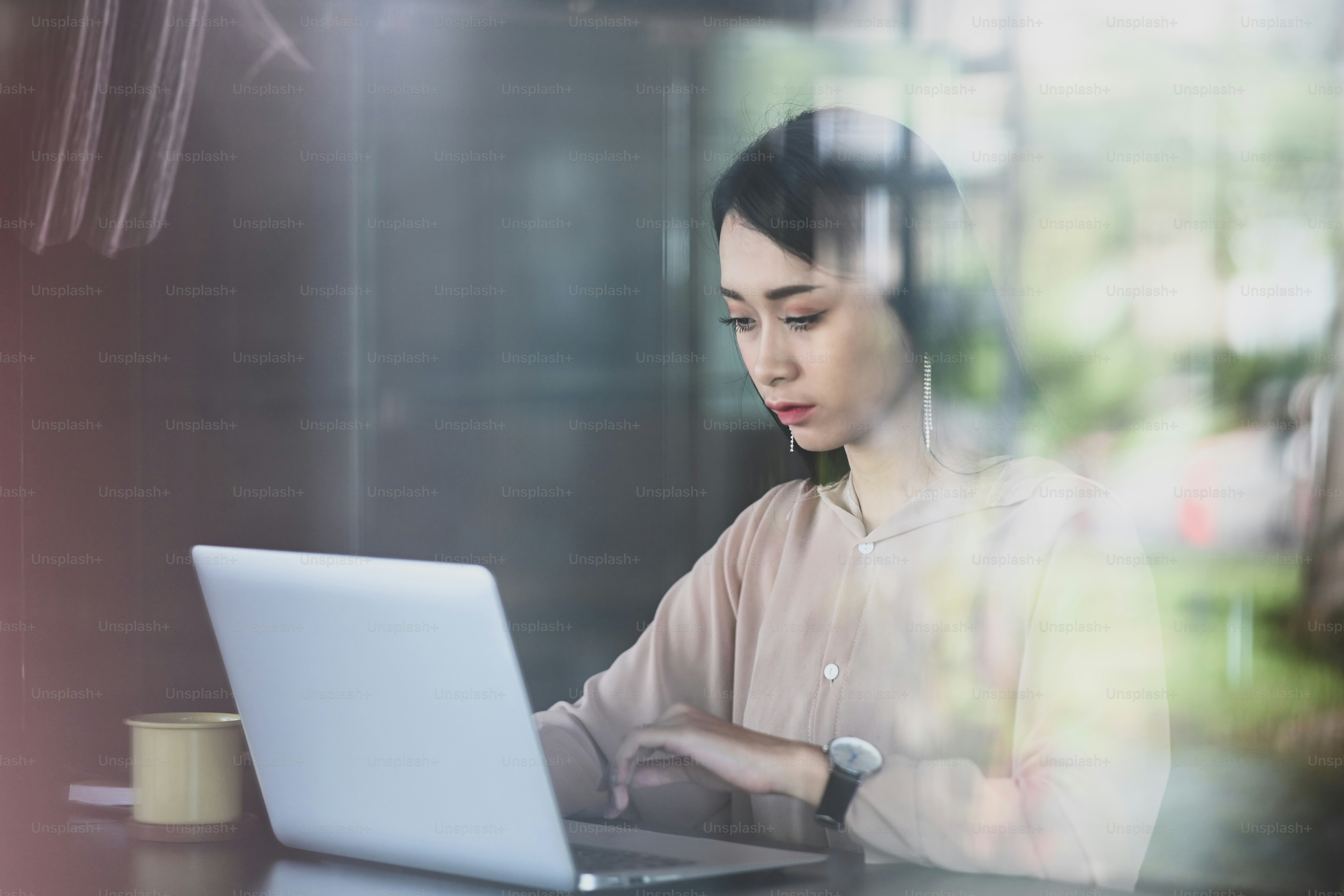 Businesswoman concentrate working on laptop computer seen through glass ...